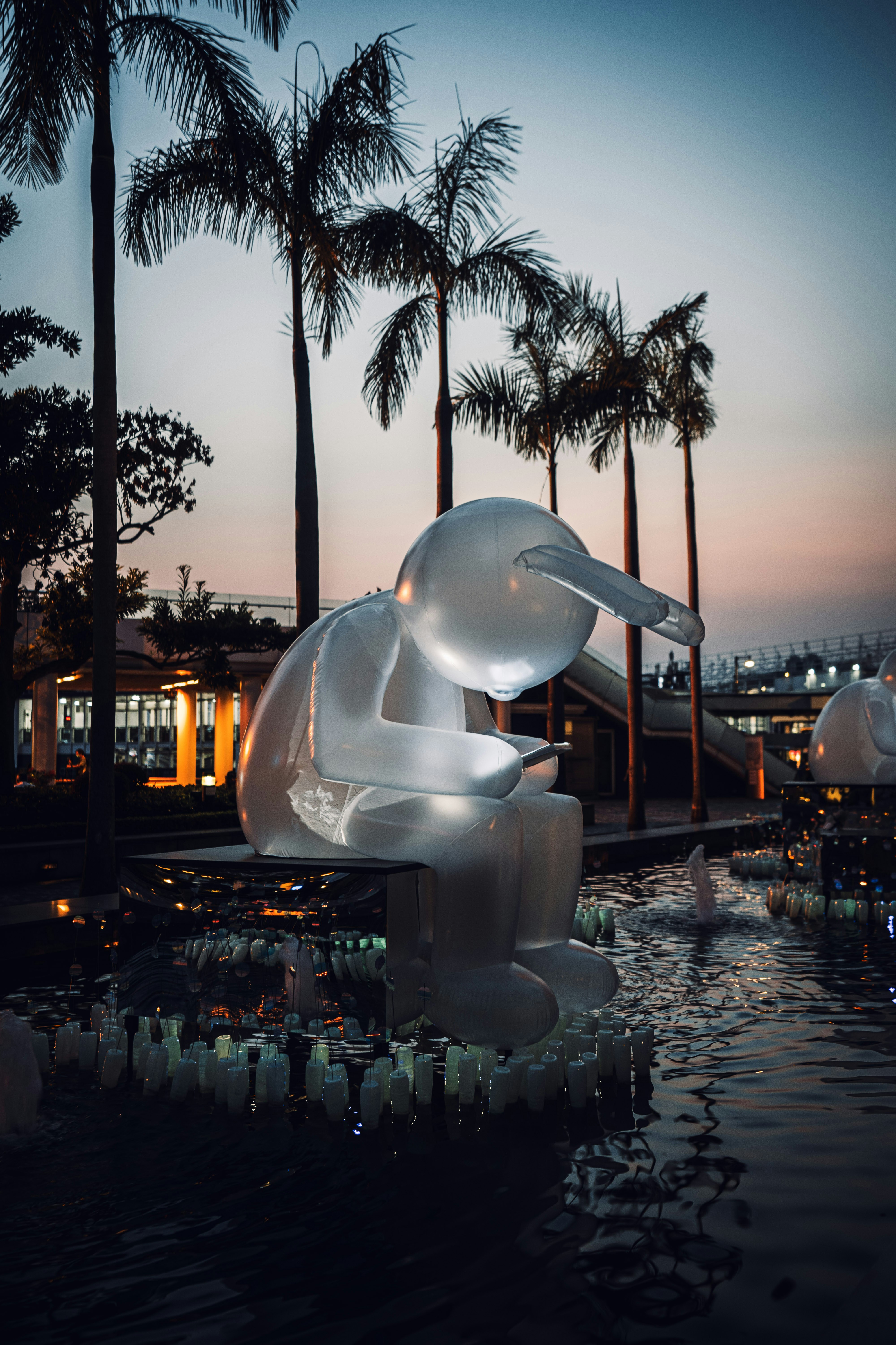 Dusk of the Liquid Figure: A Transparent Seated Vision Among Palm Shadows