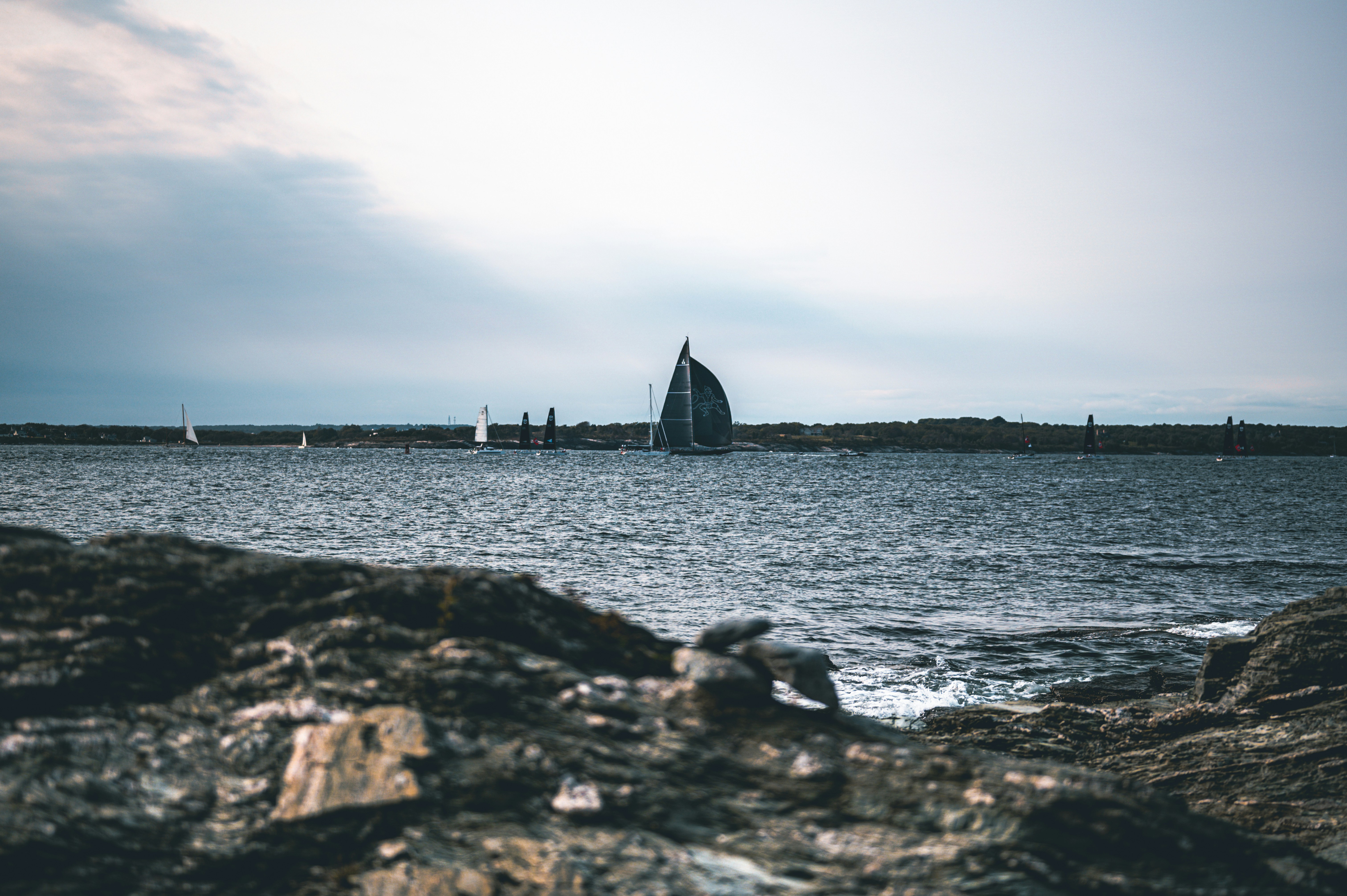 Sailboat Silhouette Across a Rocky Foreground at Dusk