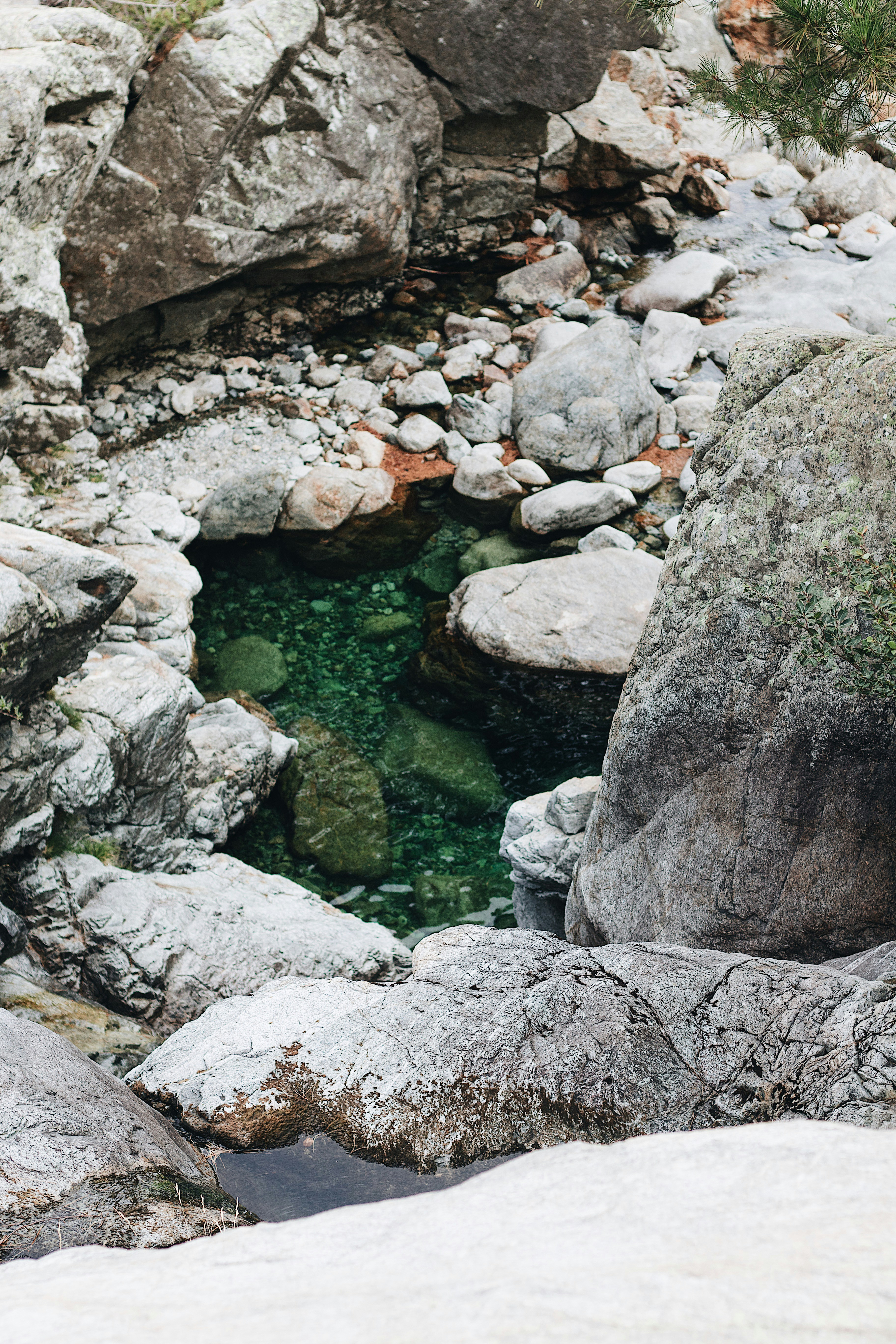 A small pool of water surrounded by rocks photo – Free Rock Image on ...