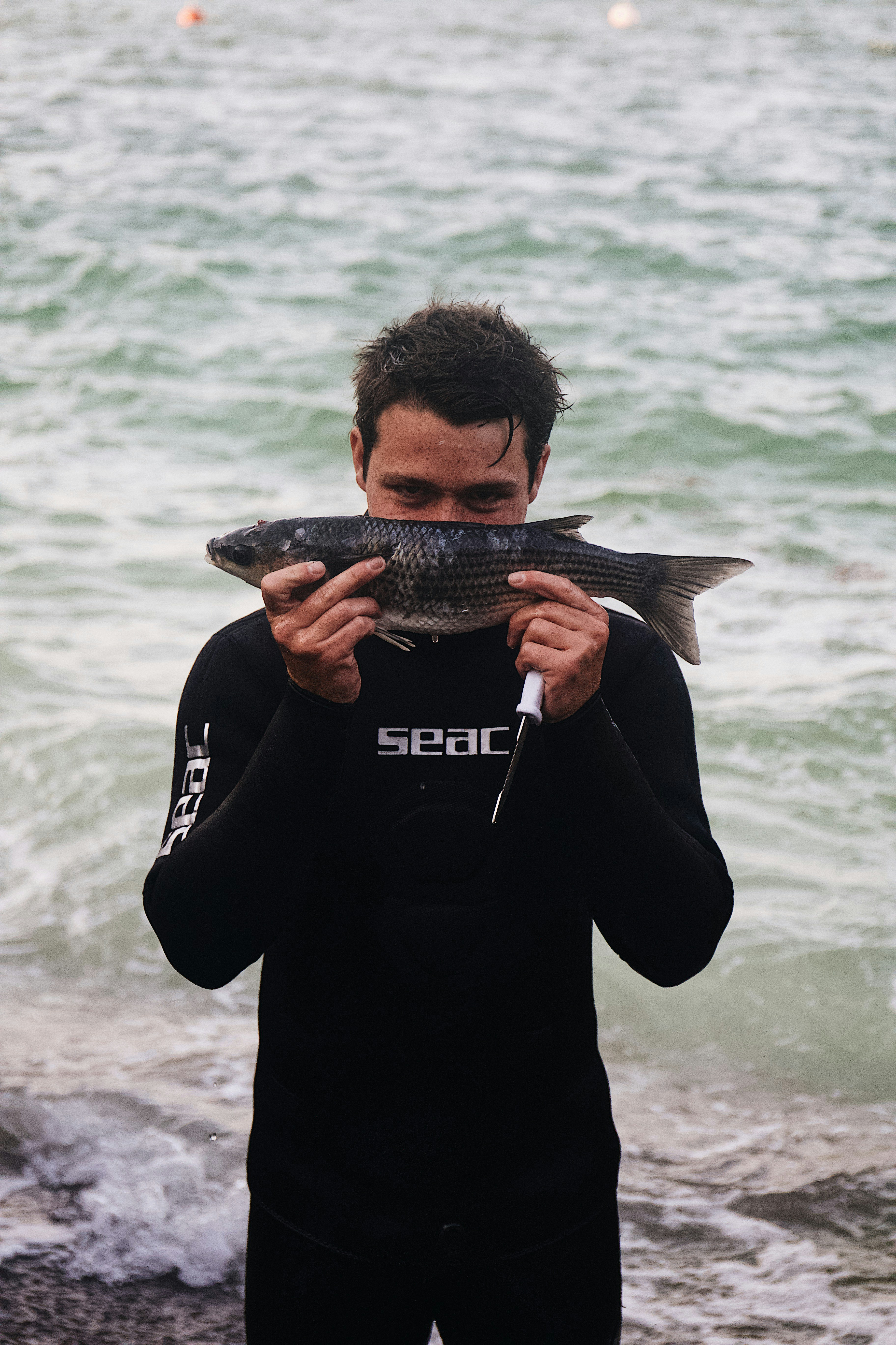 A man holding a fish in front of his face photo – Free Human Image on ...
