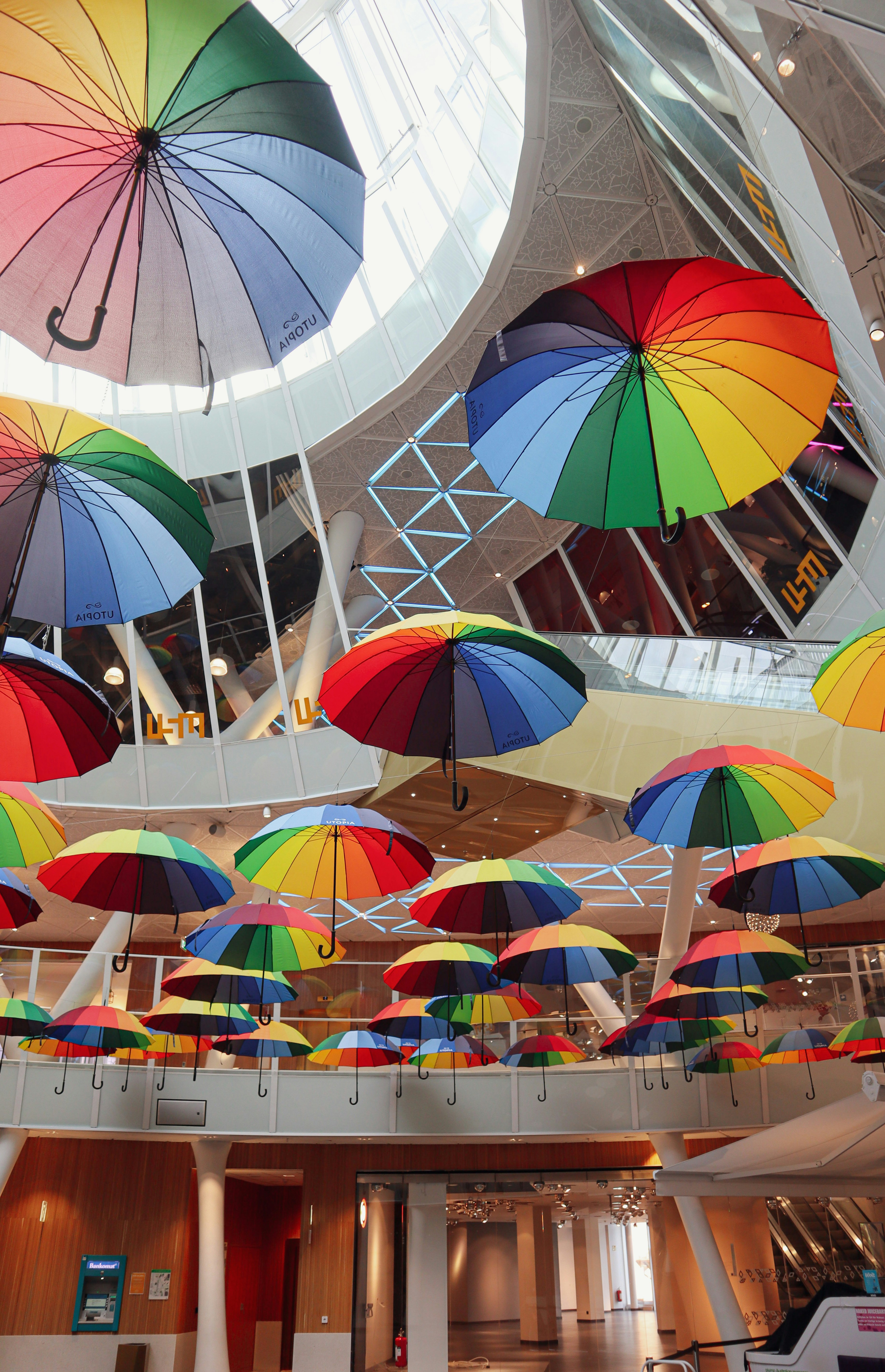 A group of colorful umbrellas hanging from the ceiling of a building ...