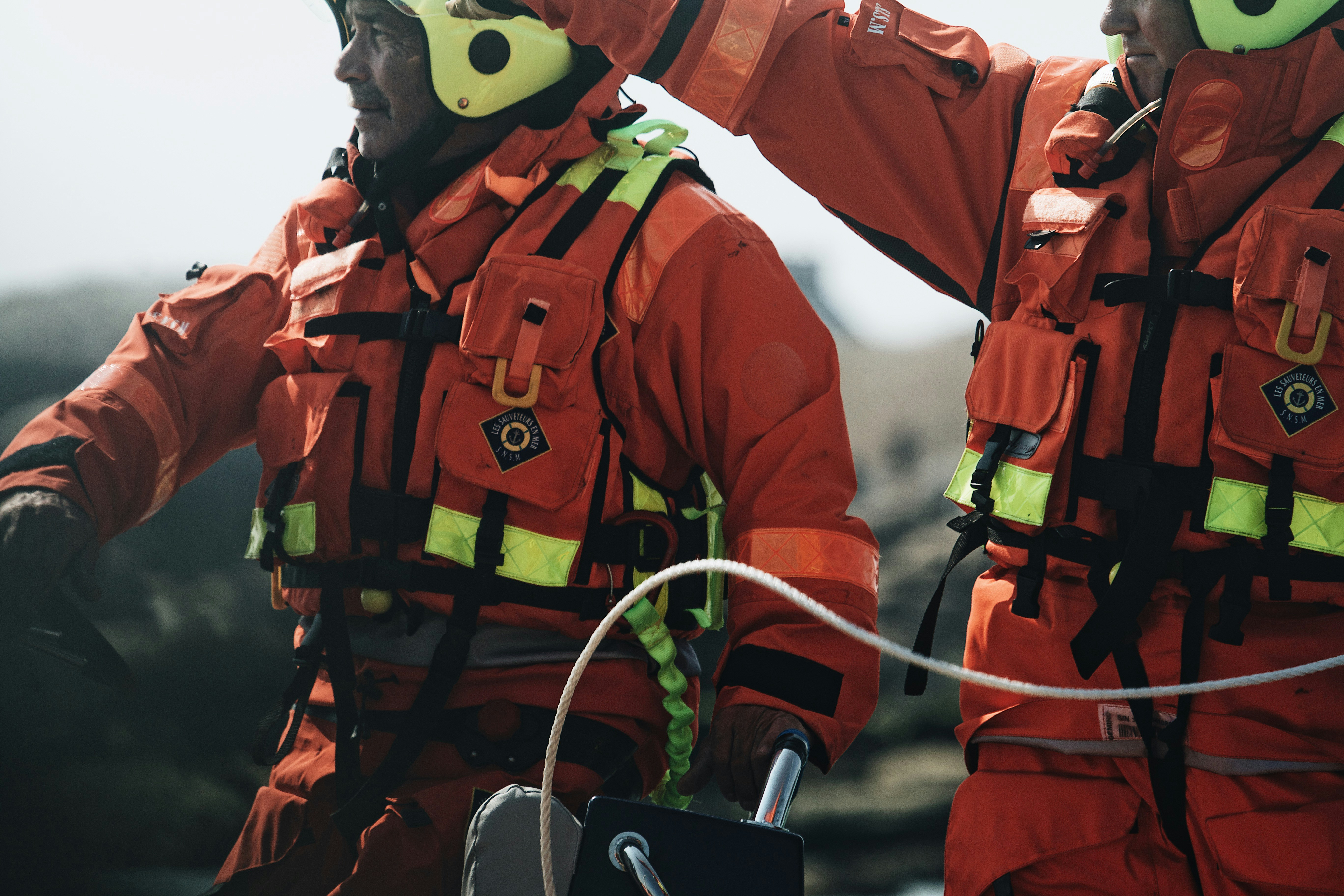 Coordinated Rescue Drill: Two Technicians in Bright Orange Gear Handling a Rope