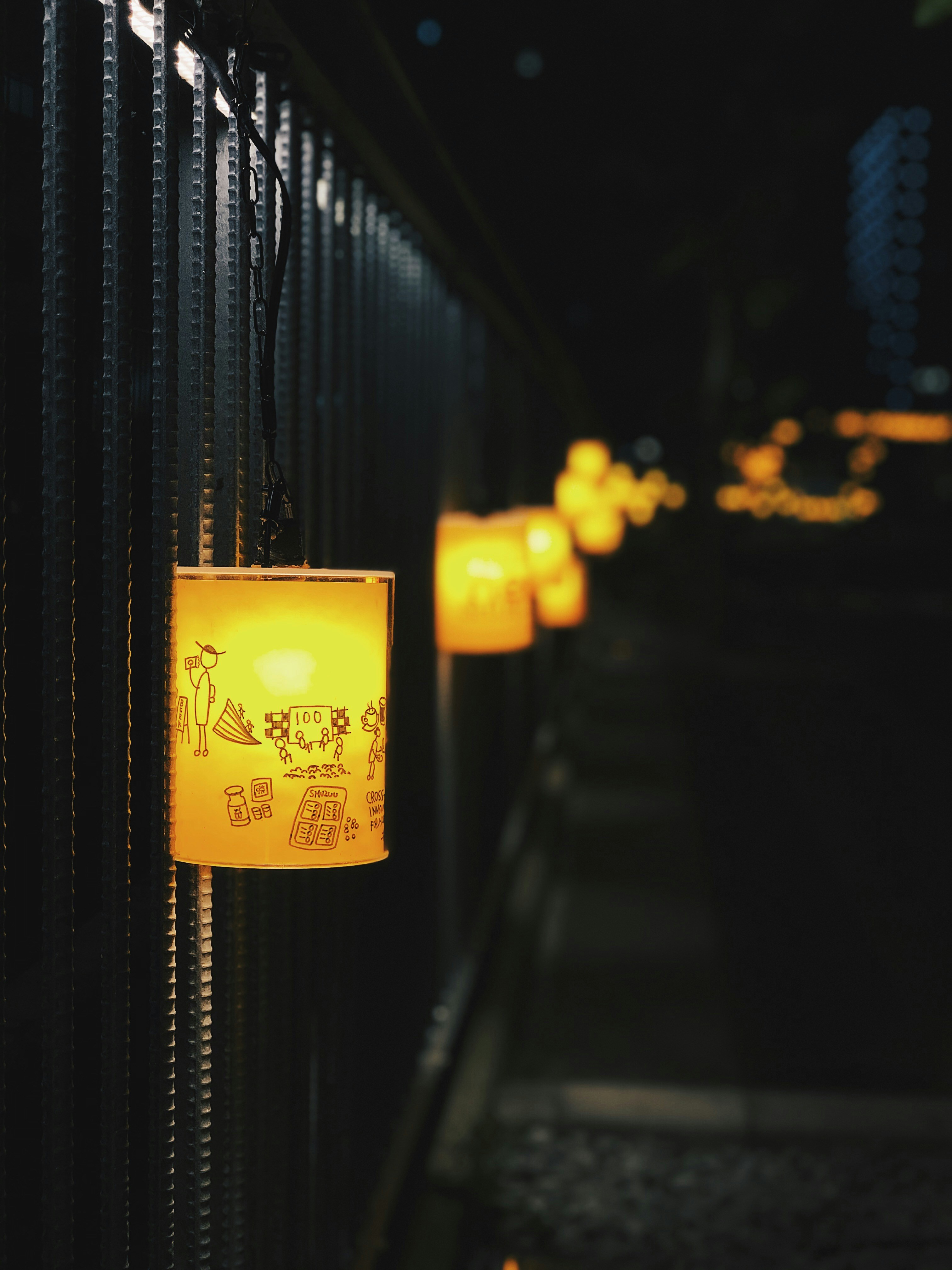 a row of yellow lights hanging from a fence