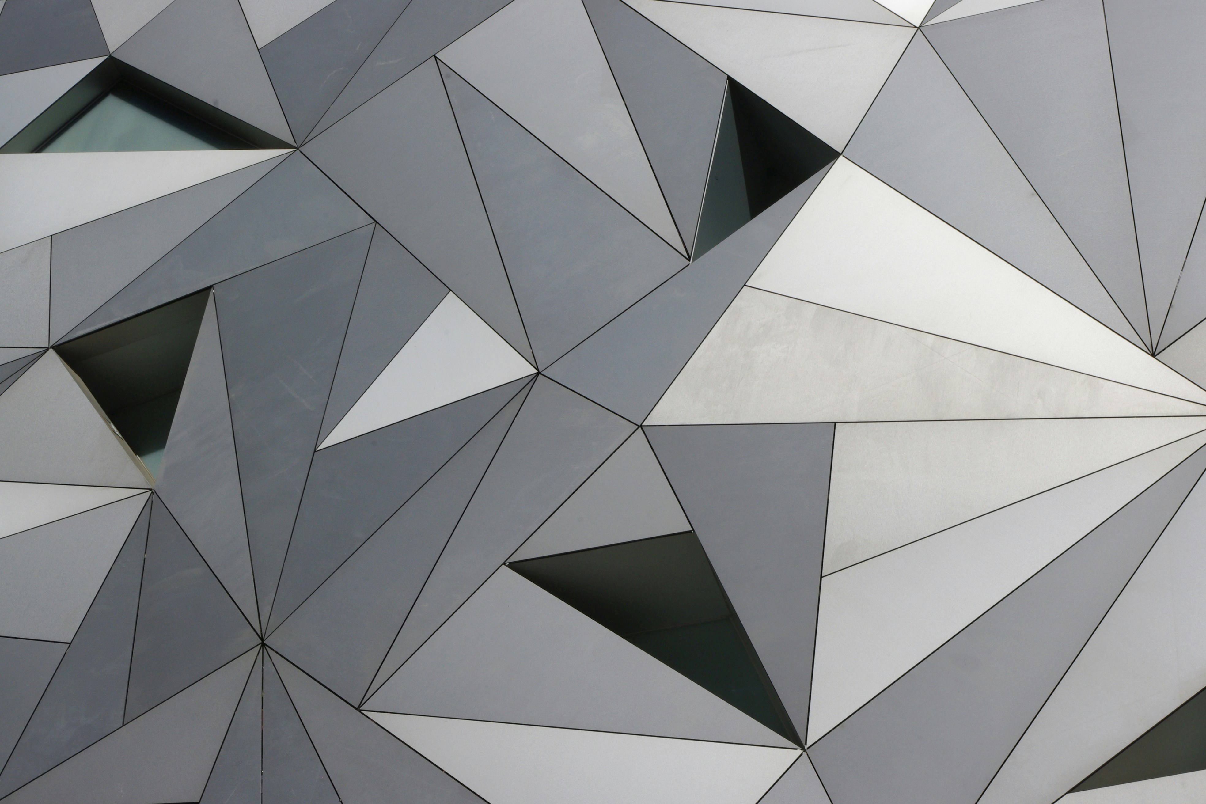 Intricate geometric patterns of a modern architectural facade showcasing a blend of triangular shapes and varying shades of gray.