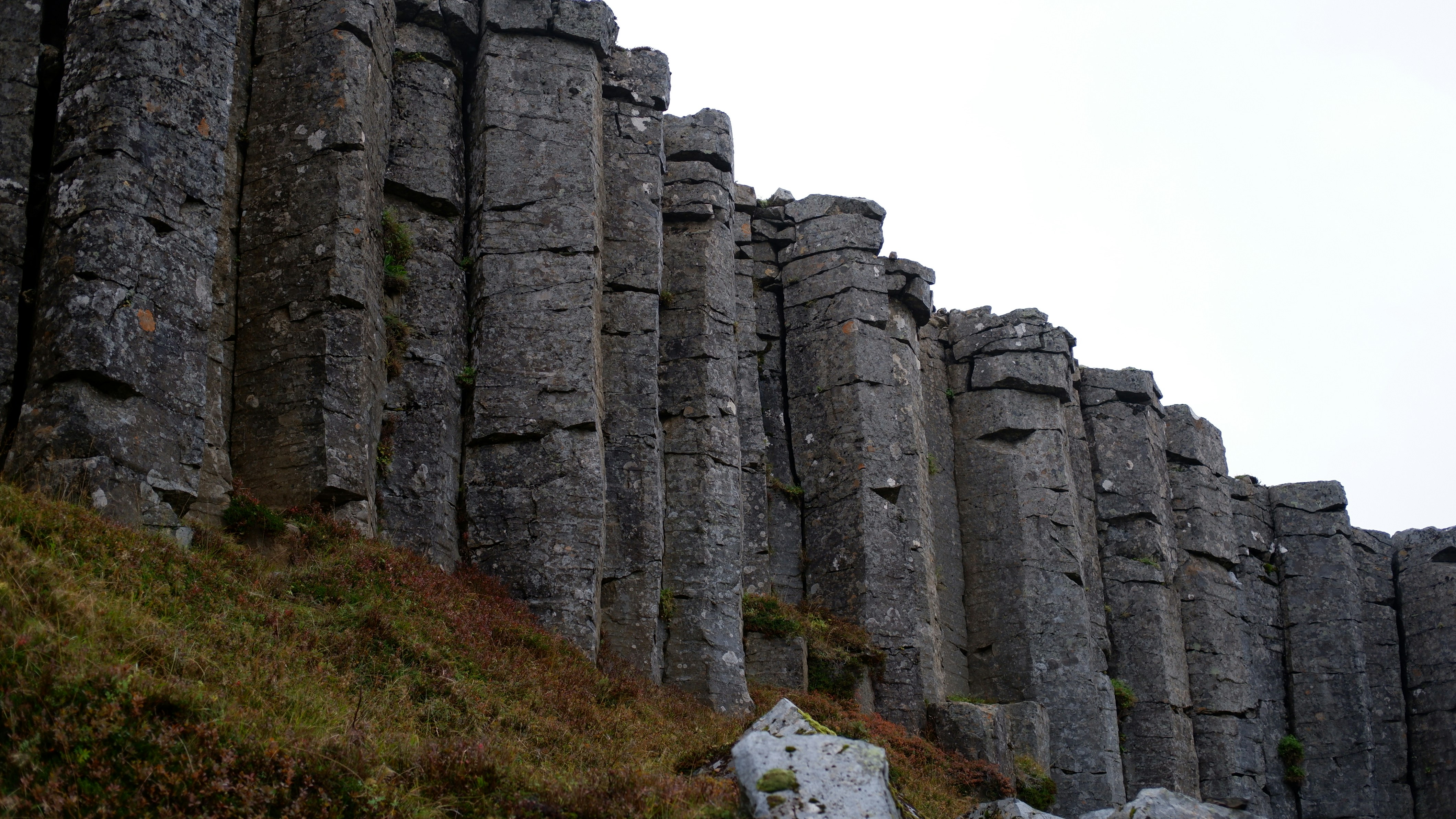 a large group of rocks sitting on top of a lush green hillside
