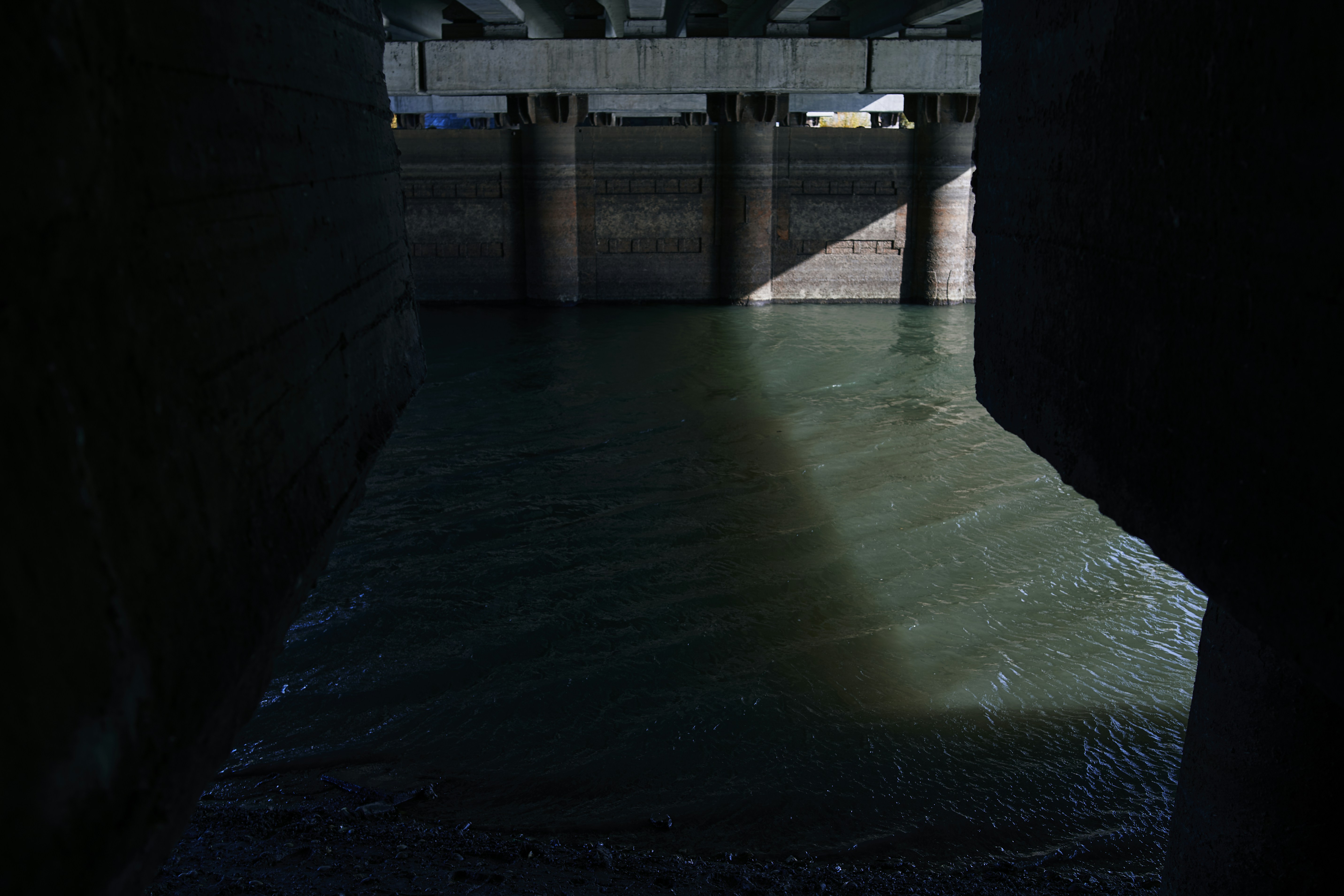 Between Pillars: A Sliver of Light on Canal Water Under the Bridge