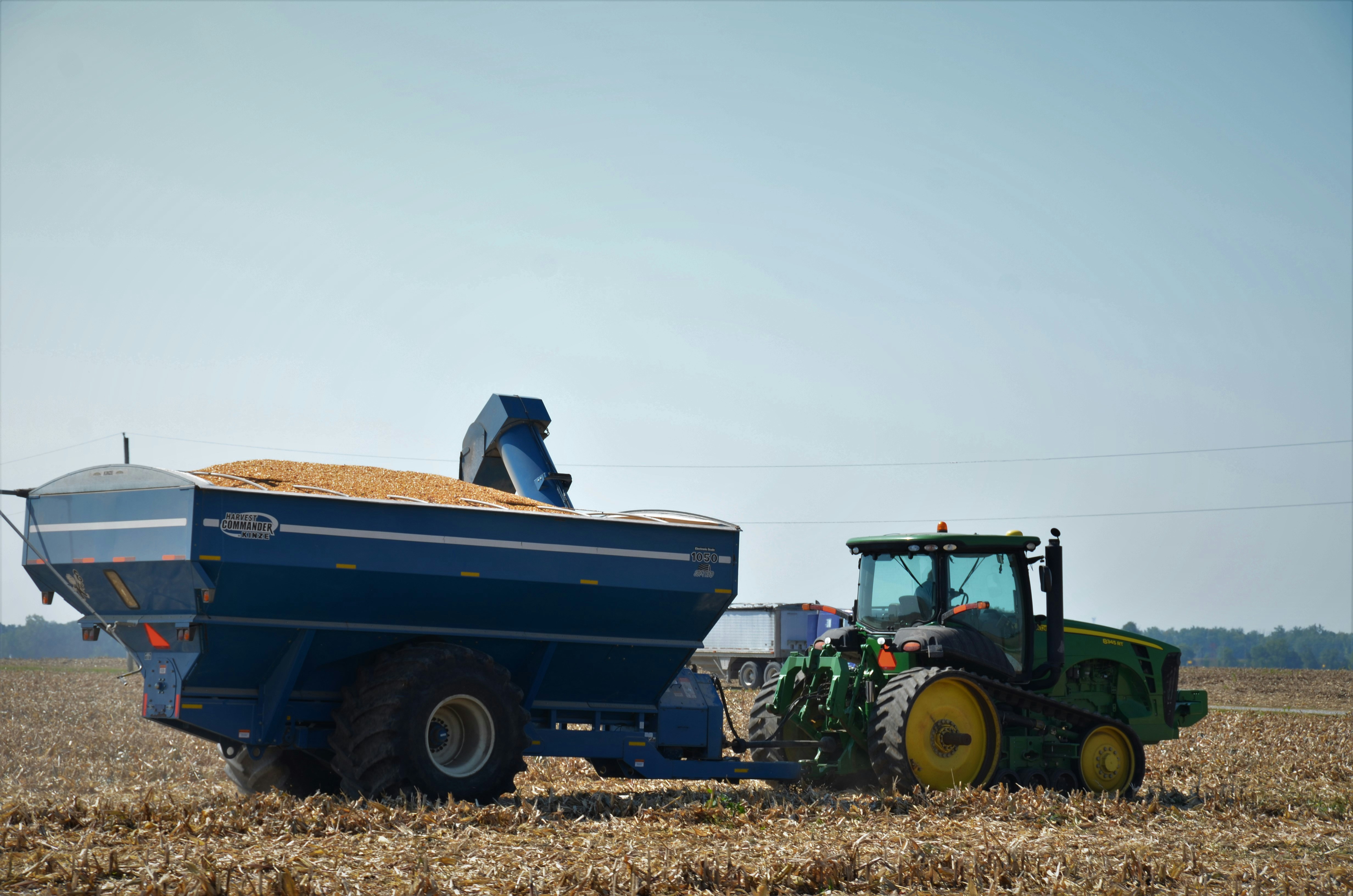 Harvest Transport: Tractor and Auger Trailer in a Sunny Field