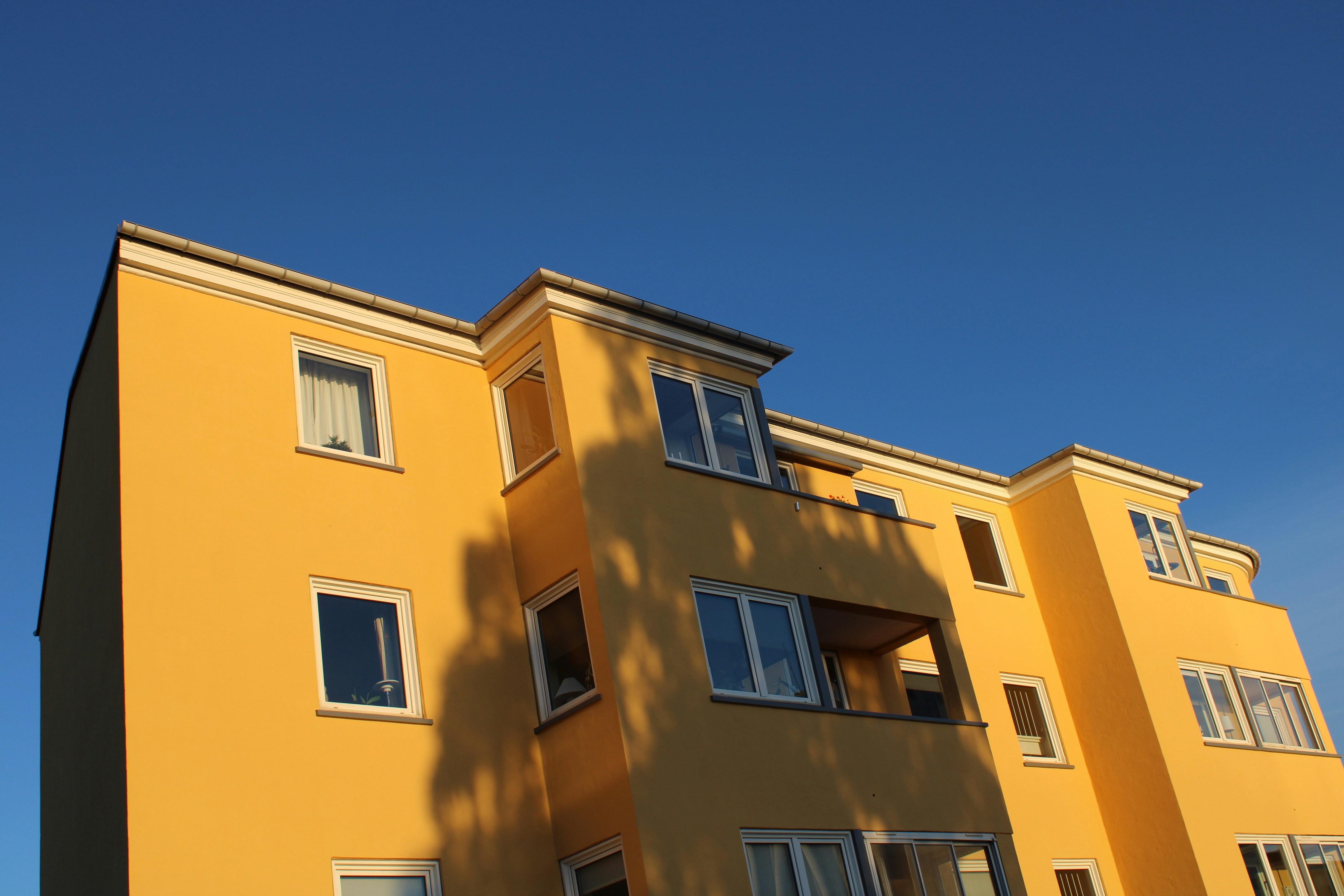 A tall yellow building with windows and balconies photo – Free Building ...