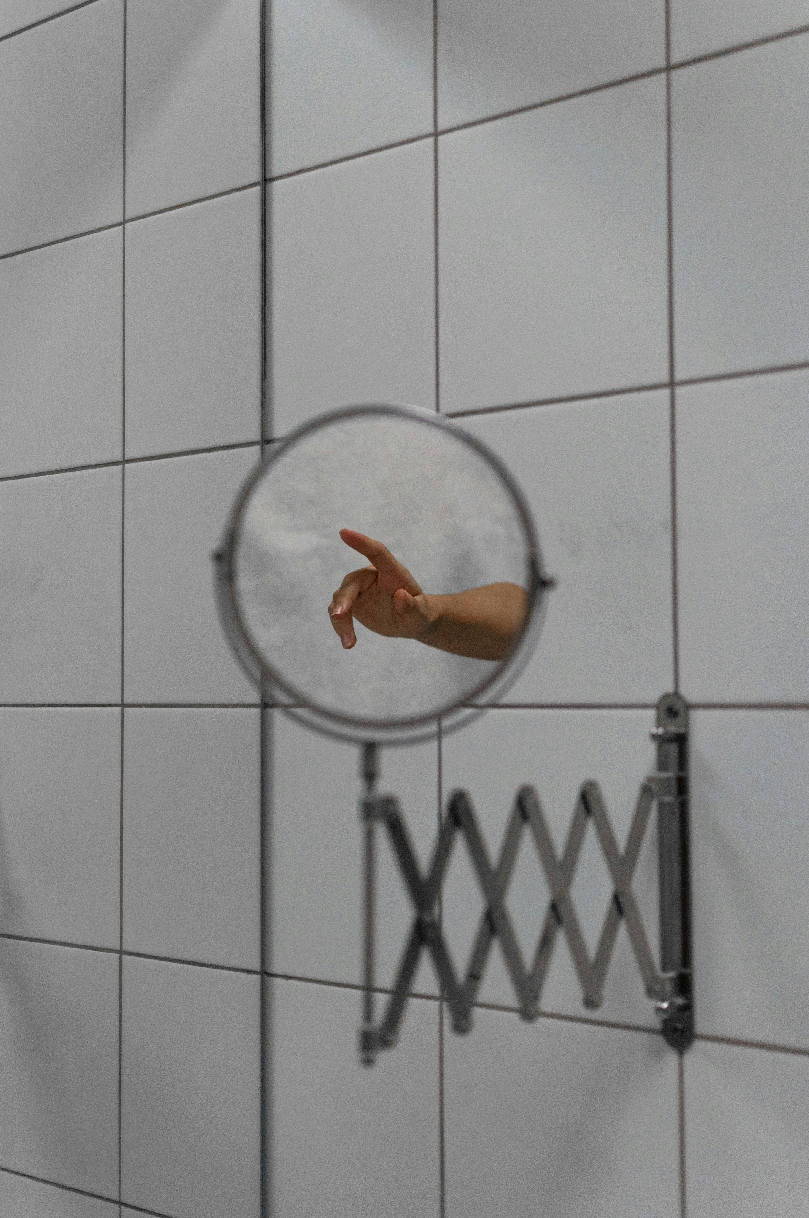 Circle in Focus: A Hand Reflected in a Wall-Mounted Mirror