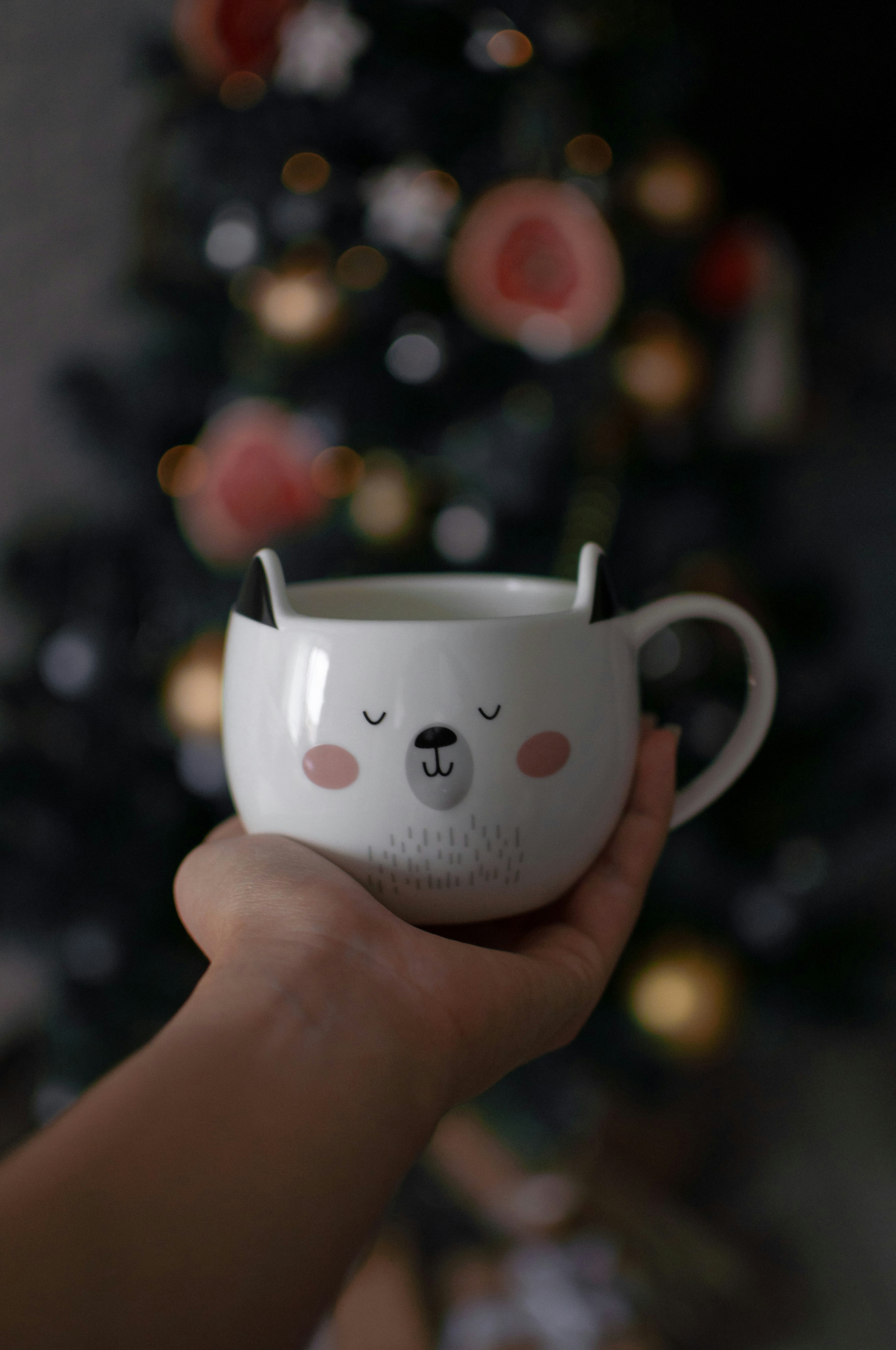 Smiling Mug in Focused Hand with Blurred Holiday Lights