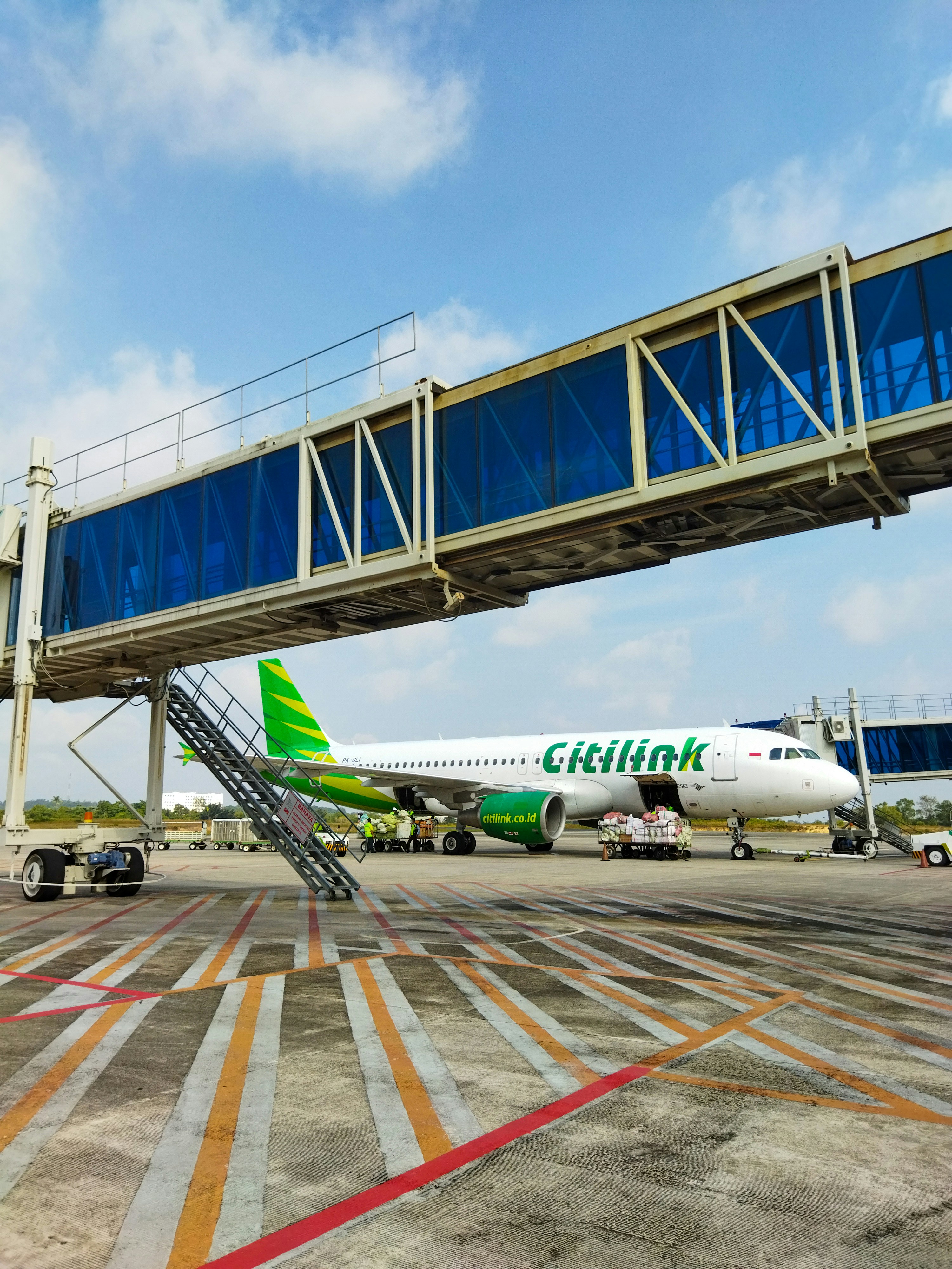 Citilink aircraft parked at the terminal, with a boarding bridge and service vehicles in view. The scene captures the essence of air travel logistics.