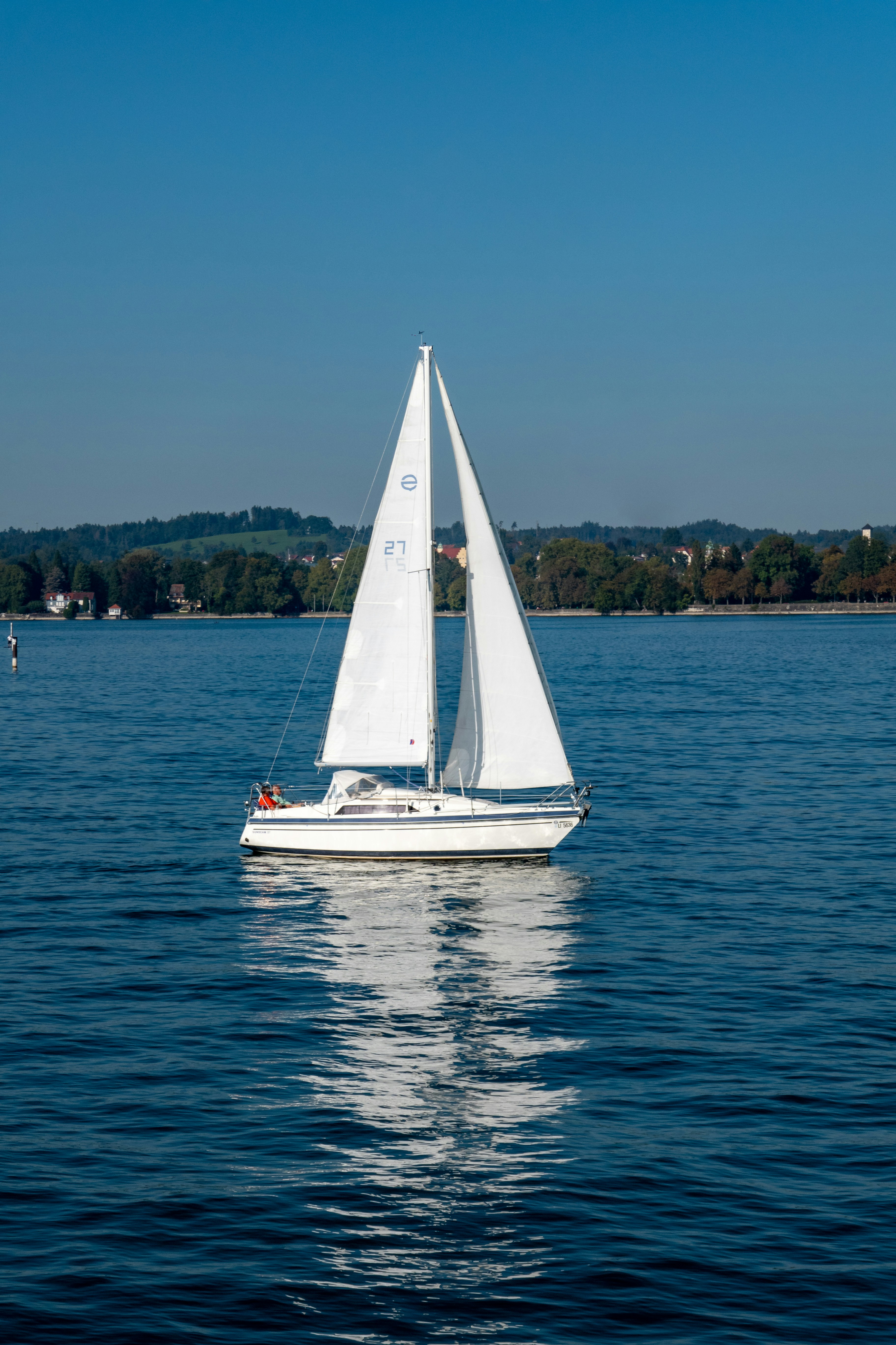 White Sailboat | a white sailboat floating on top of a large body of water