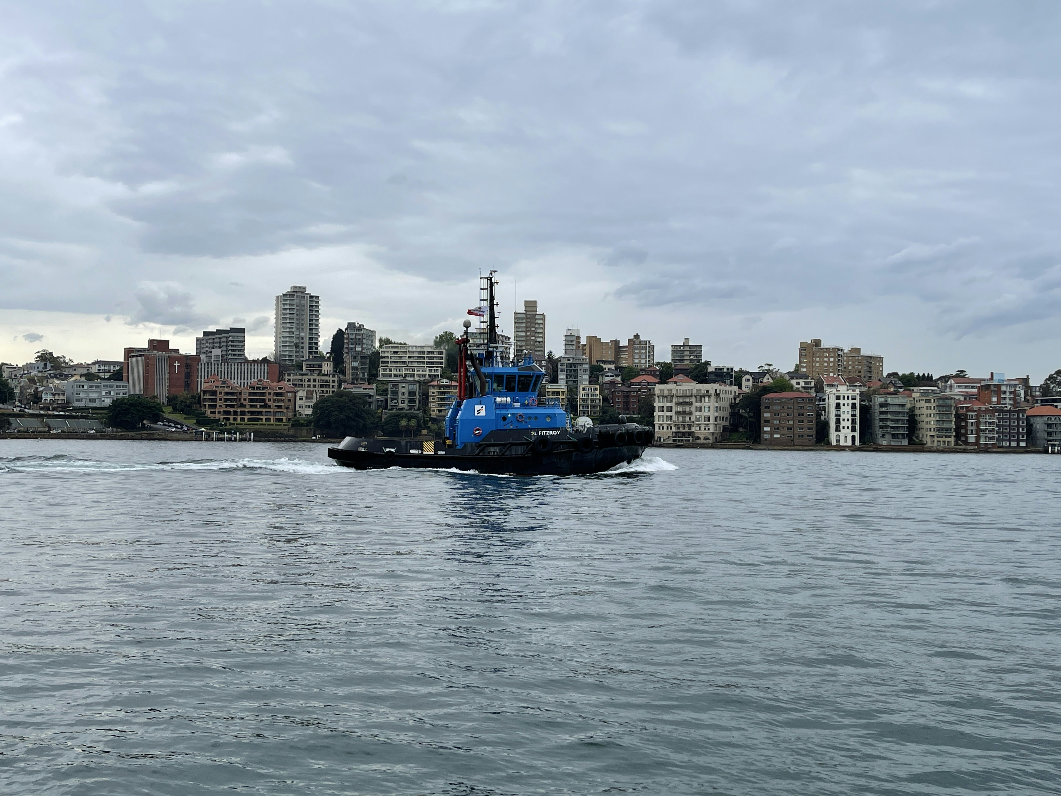 a tug boat in a body of water with a city in the background