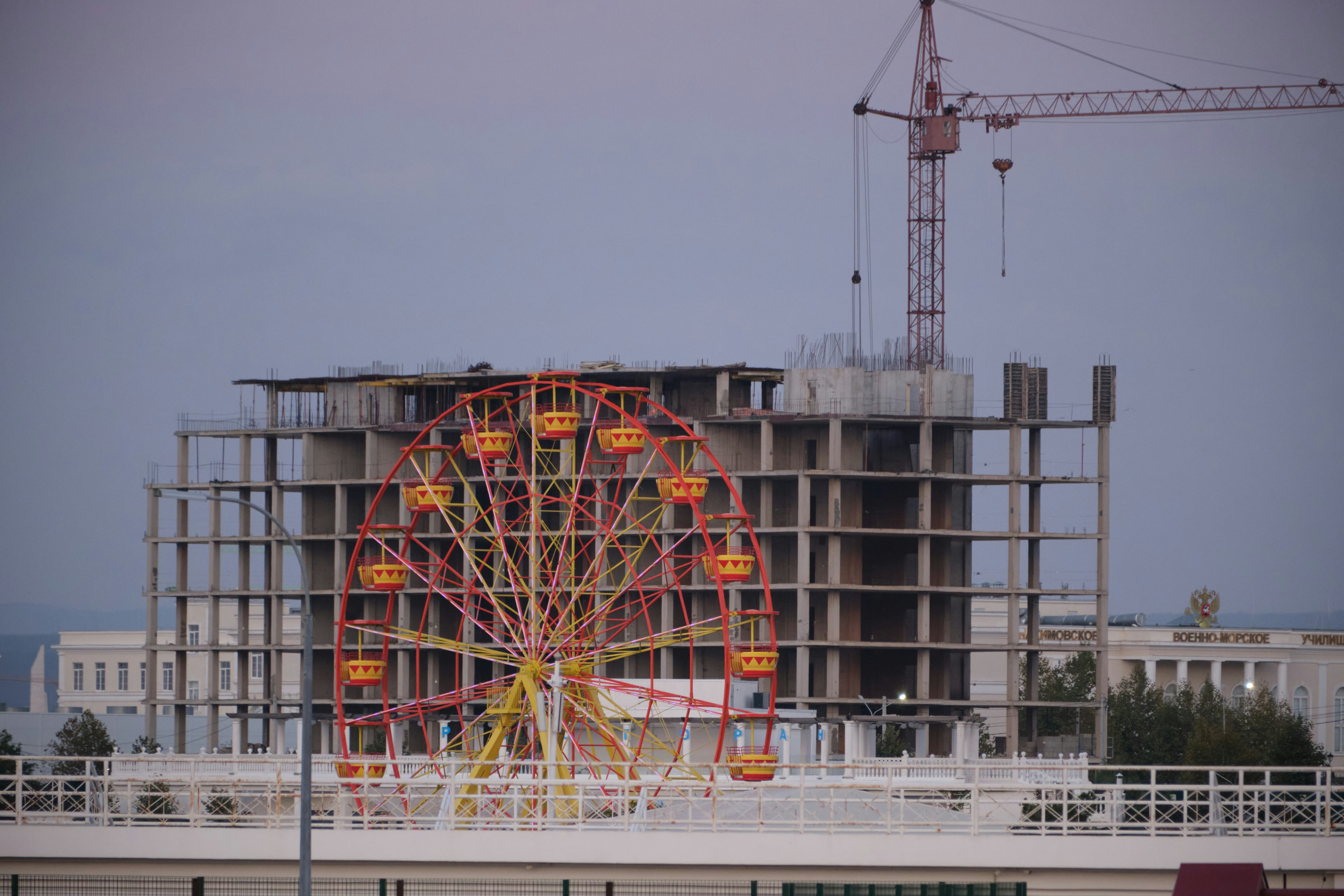 Ferris Wheel Under Construction: Colorful Spokes Rise Above a Skeletal Building Site