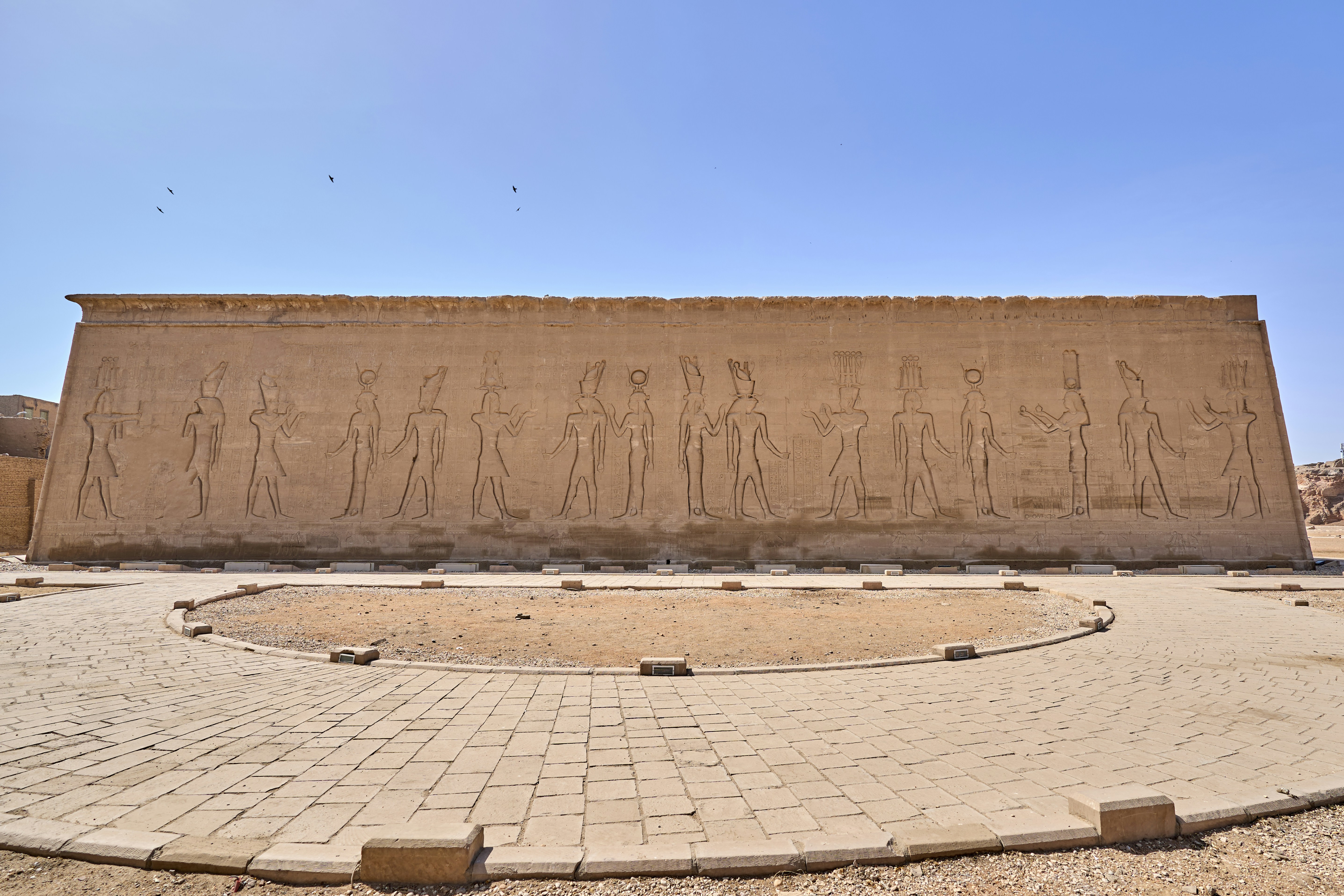 Intricate carvings of ancient Egyptian deities adorn the temple wall at Karnak, showcasing historical artistry and reverence. The scene captures the grandeur of this archaeological site.