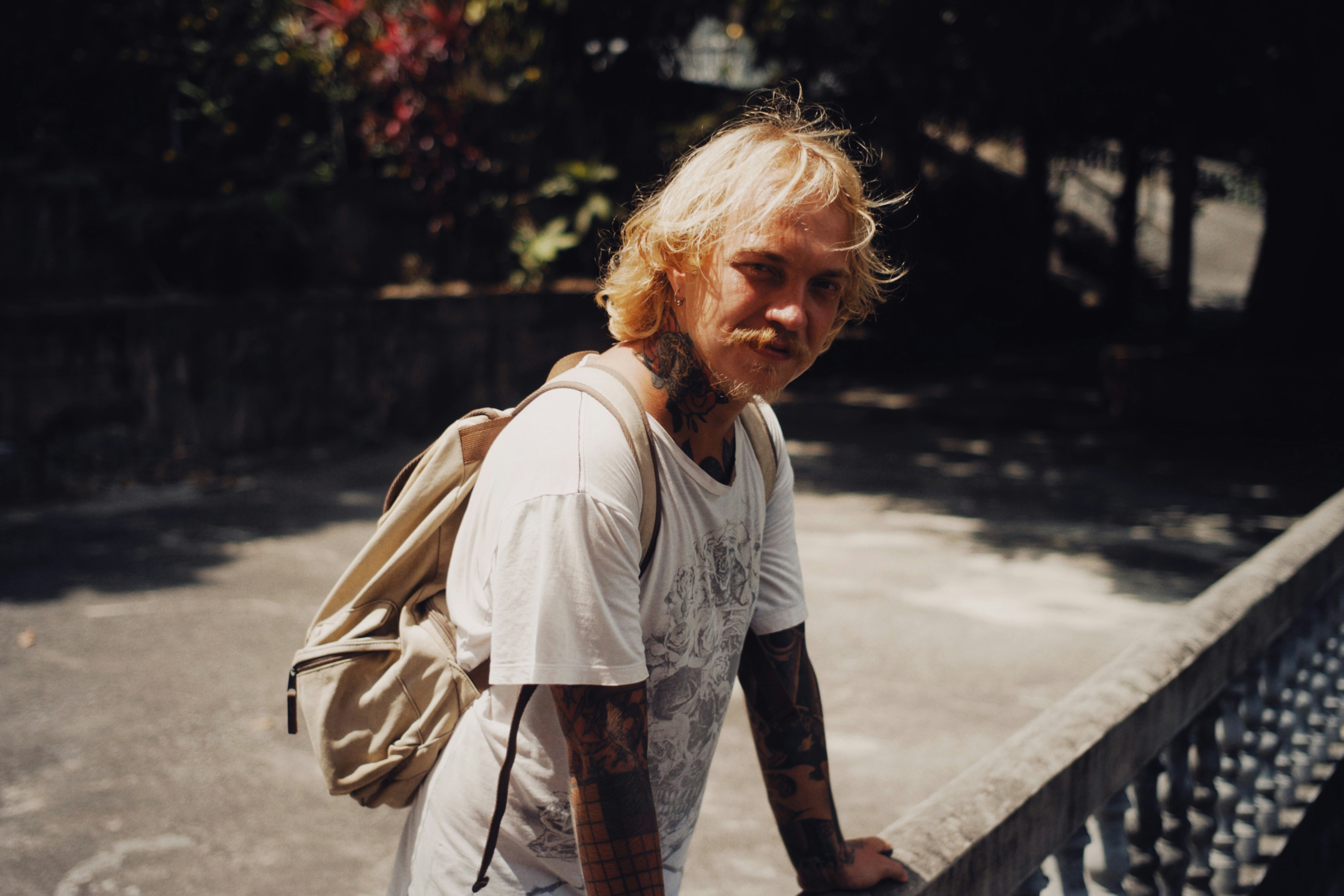 A man with tattoos on his arm and a backpack on his shoulder photo ...