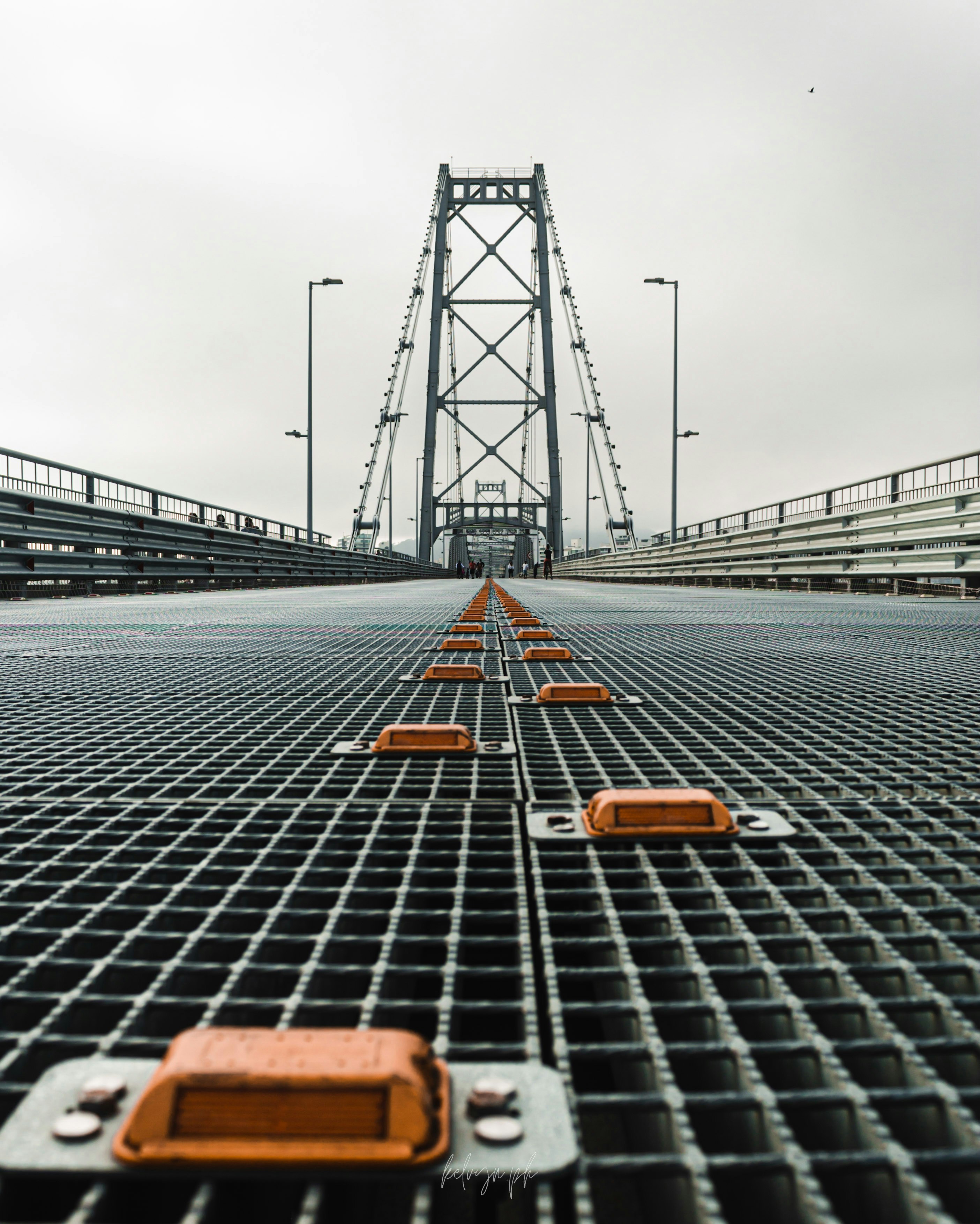 A large metal grate with a bridge in the background photo – Free ...