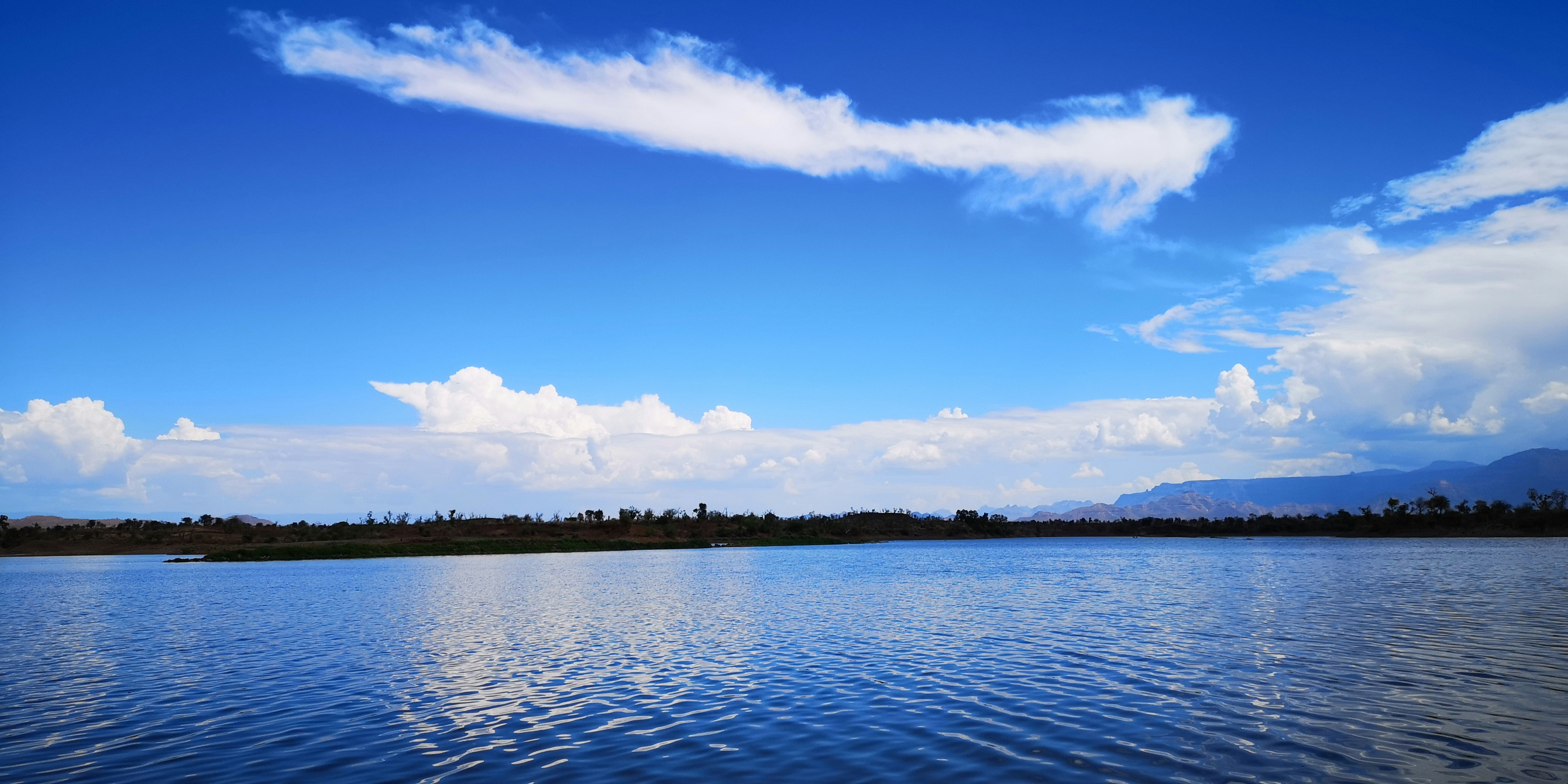 blue sky | a large body of water surrounded by mountains