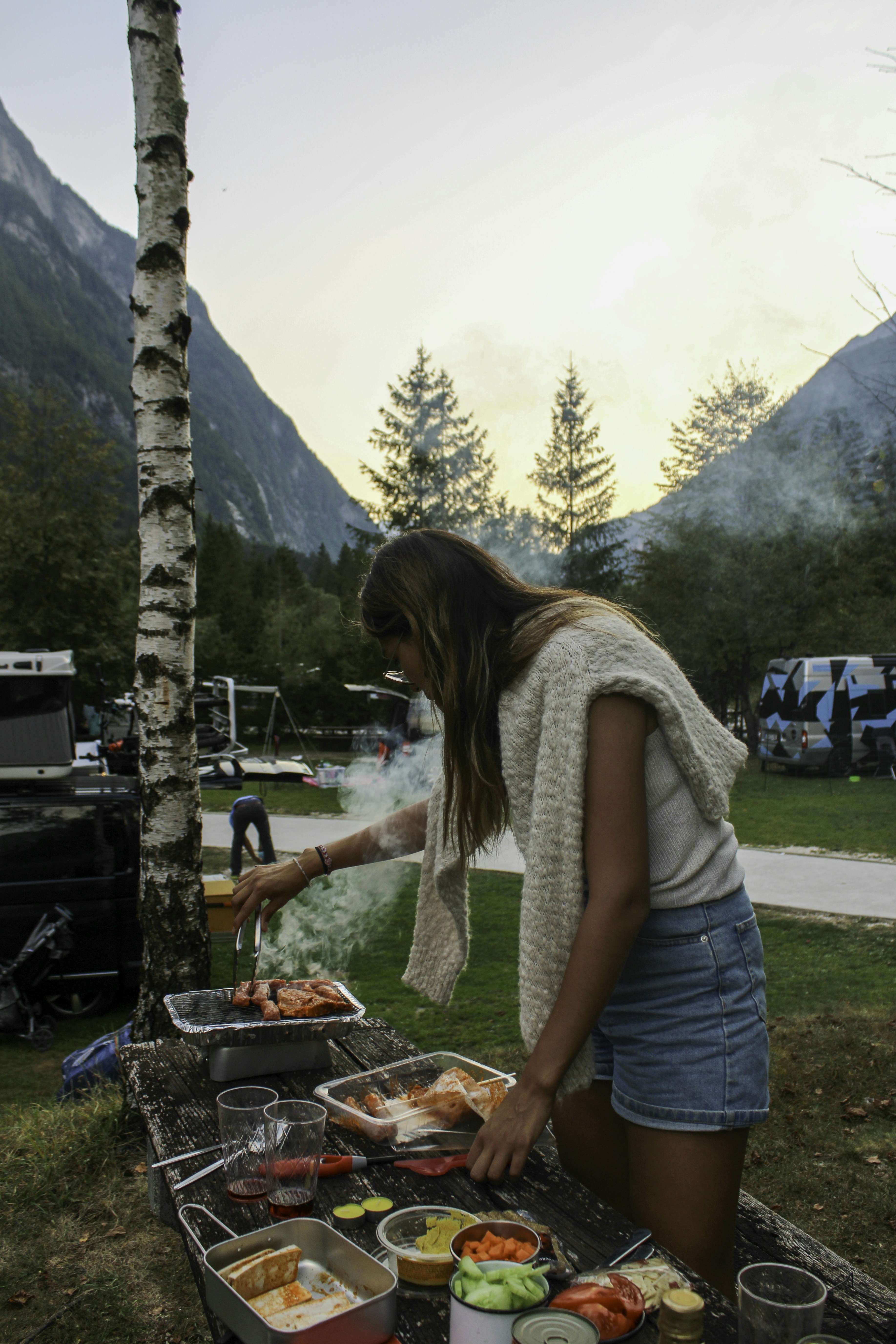 A woman standing over a table filled with food photo – Free Bovec Image ...
