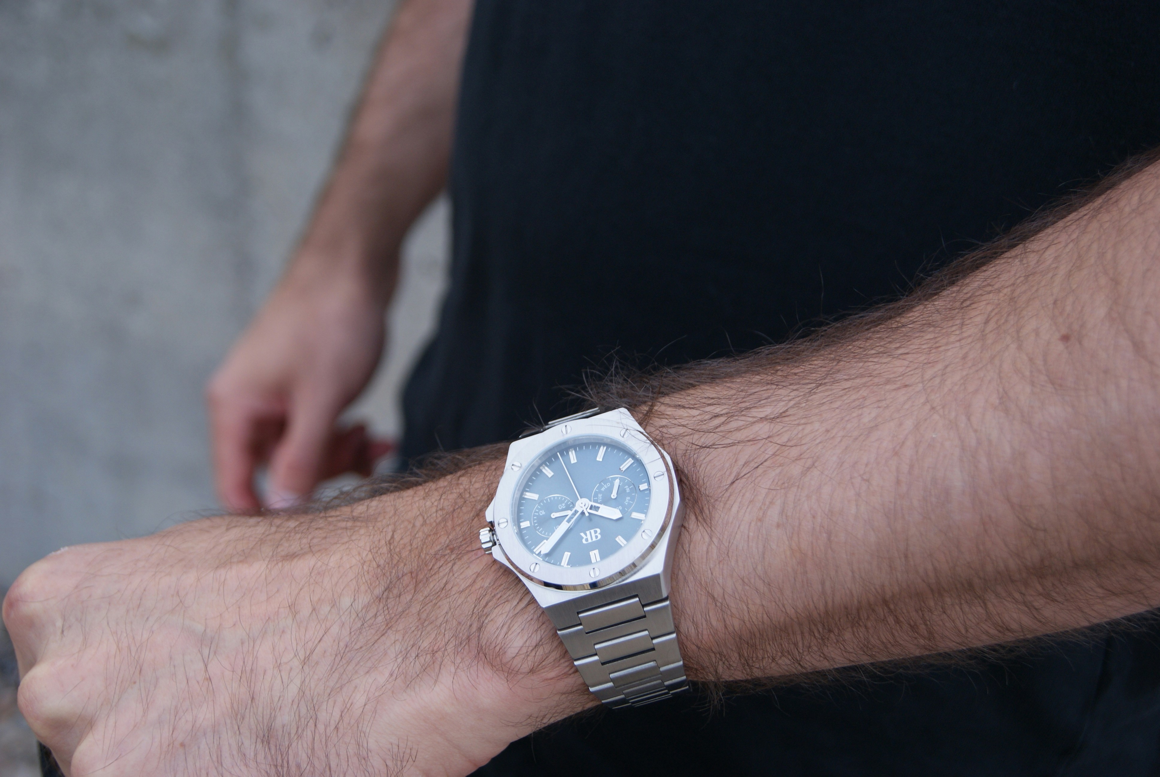 Close-up of a stylish wristwatch on a man's arm, showcasing its intricate design and metallic band.