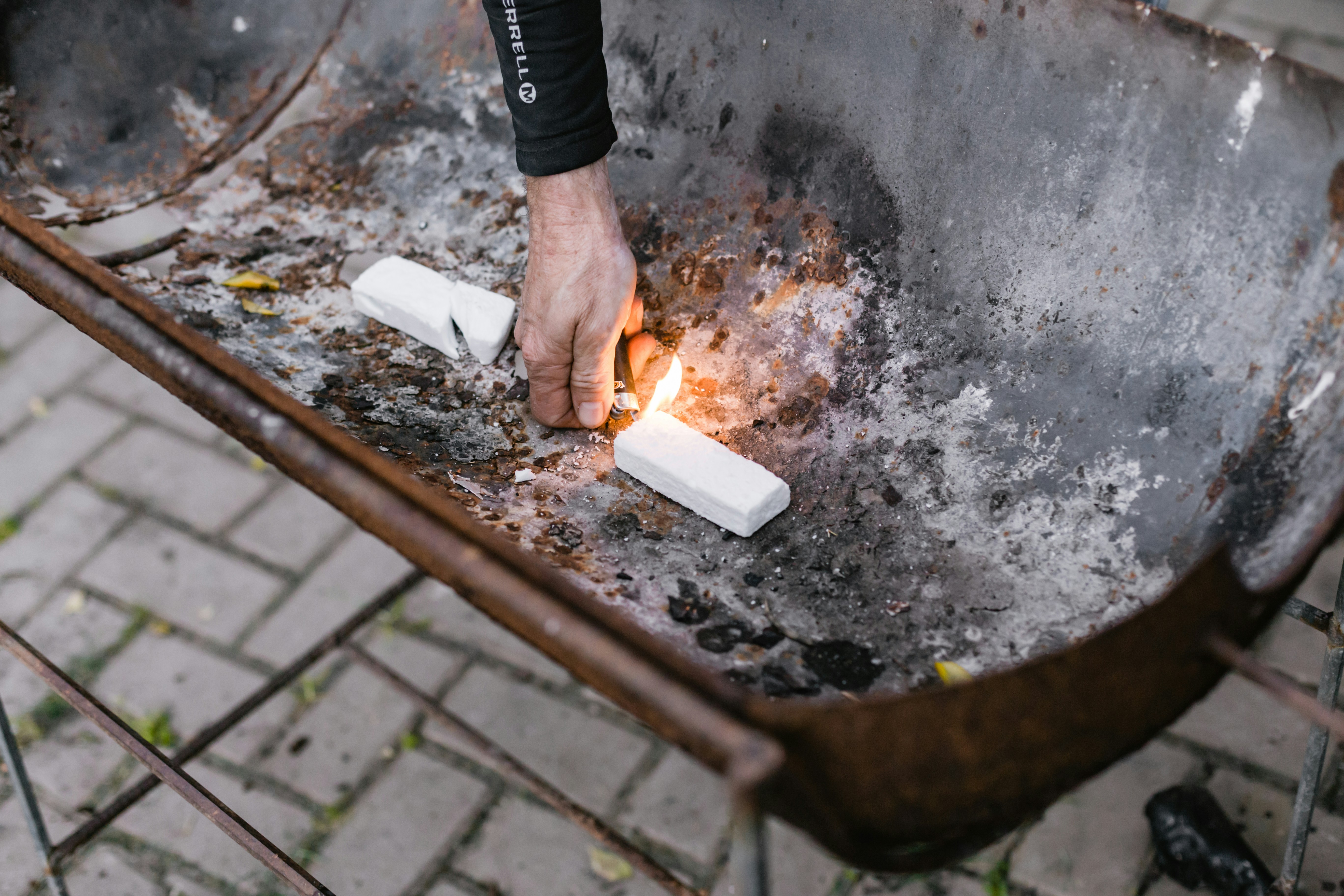 A person using a lighter to burn something on a grill photo – Free ...