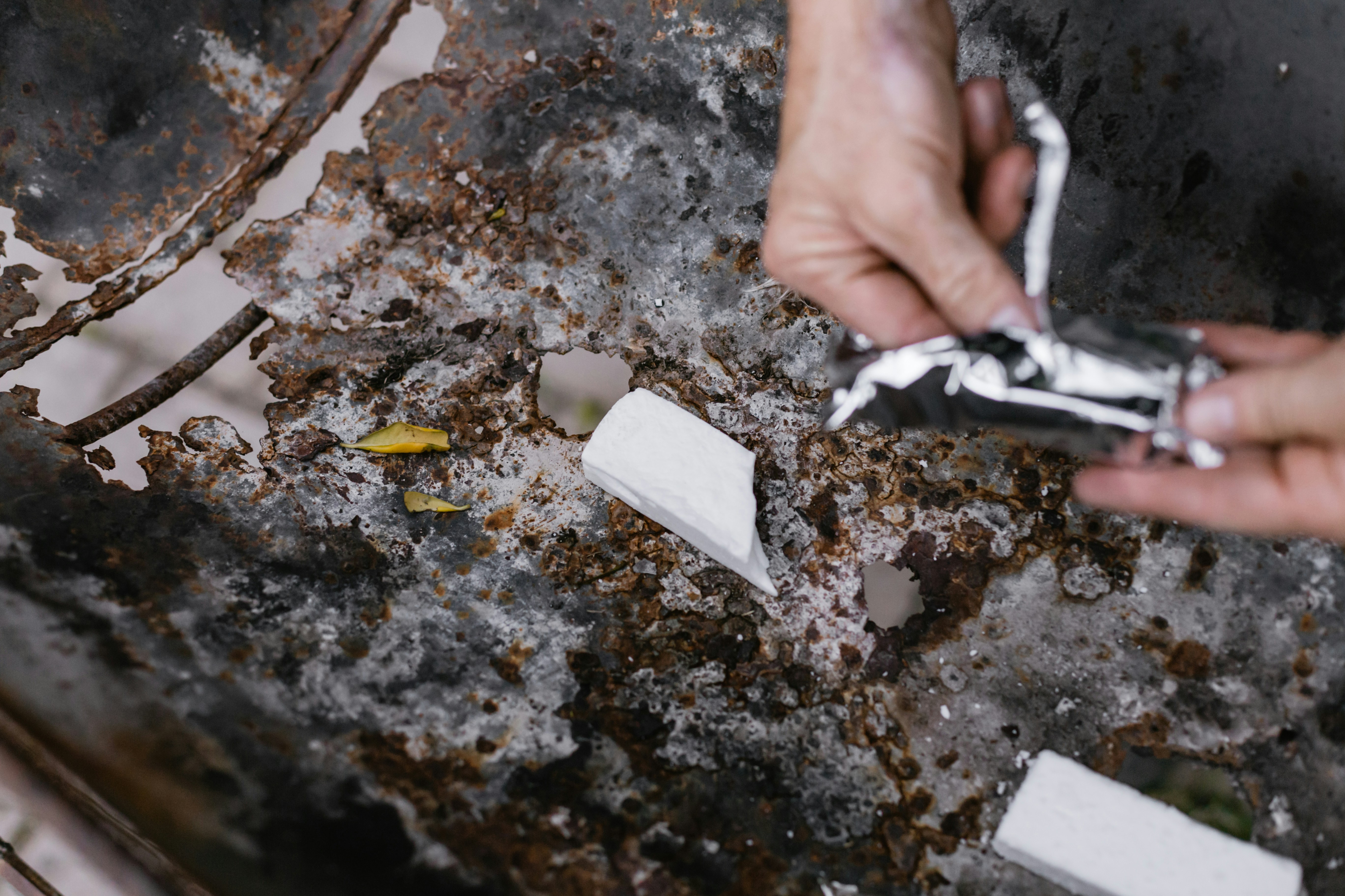 A person is peeling something off of a piece of metal photo – Free ...