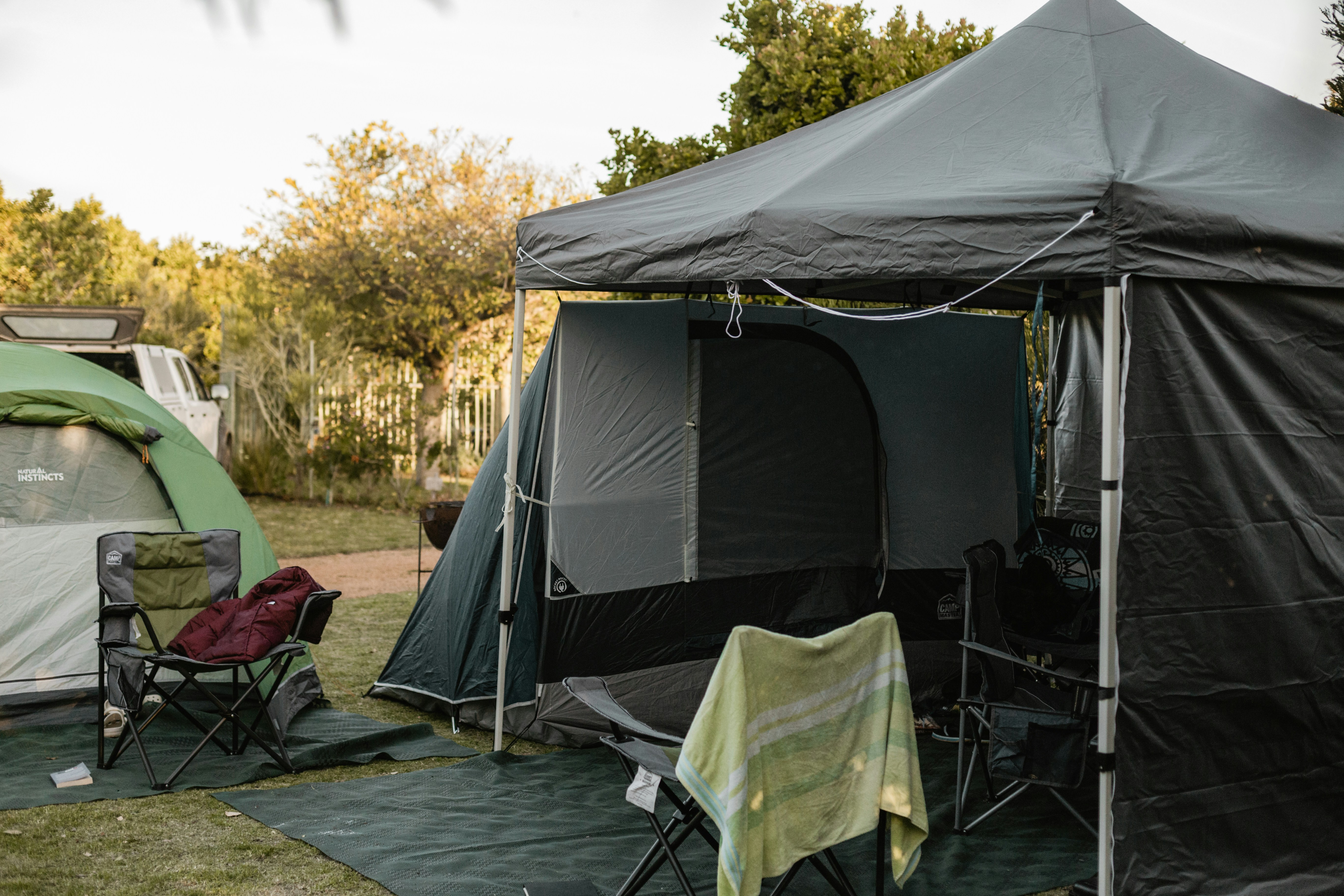 Camping setup featuring a spacious tent and folding chairs surrounded by greenery. Relaxation and outdoor adventure blend seamlessly.