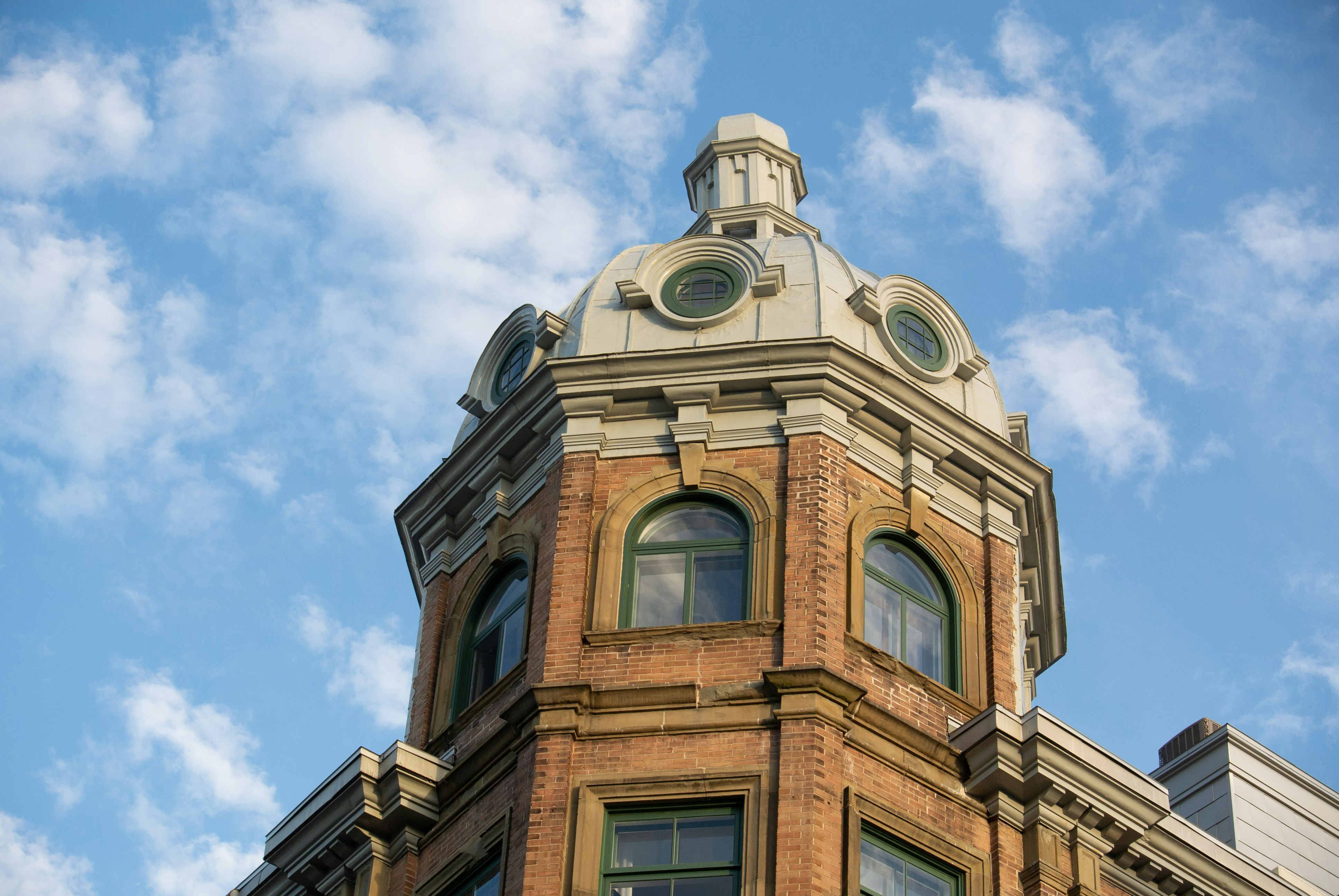 Historic building corner featuring ornate architecture and large windows against a blue sky.