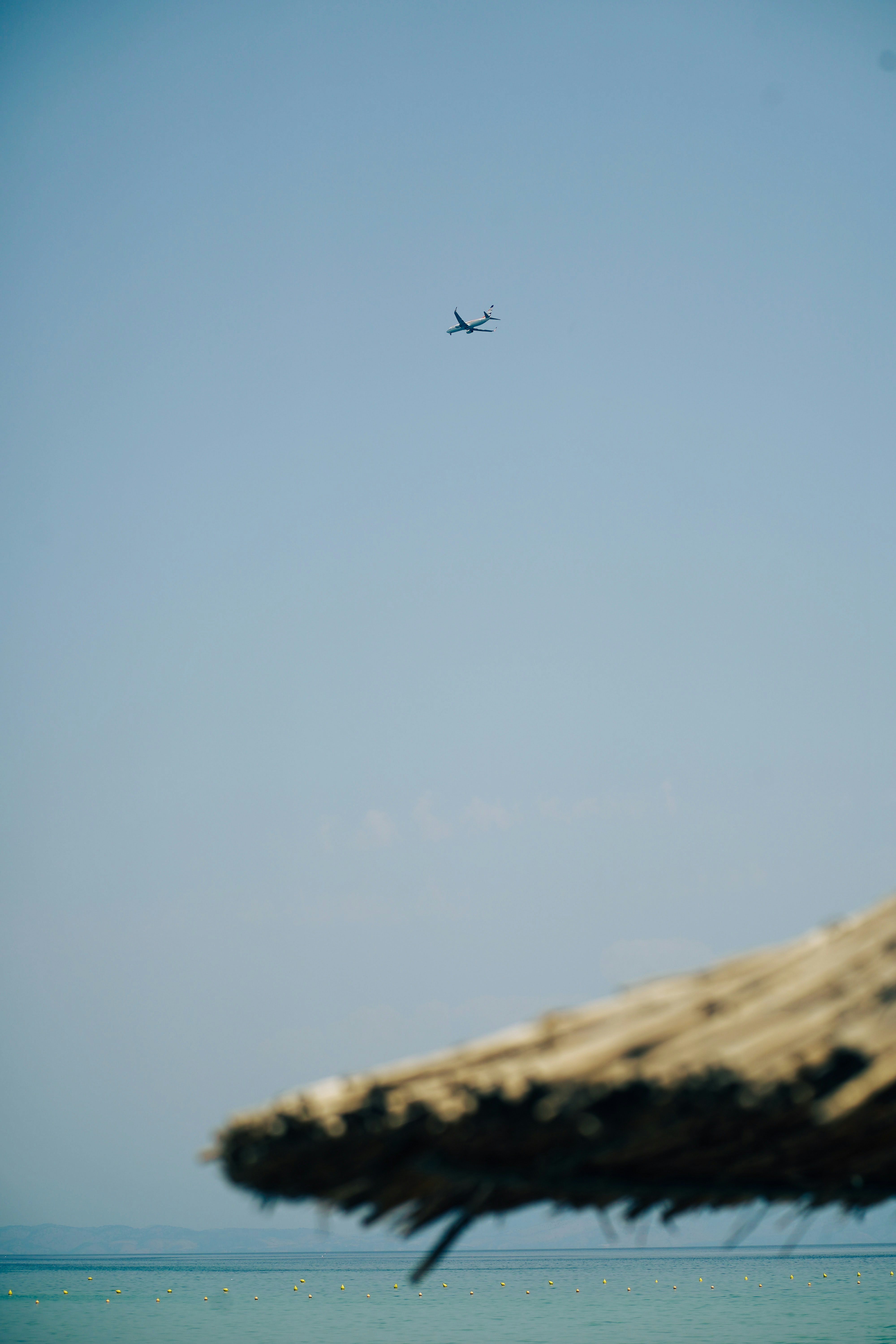 Soaring Silence: A Lone Airliner Above a Quiet Seascape