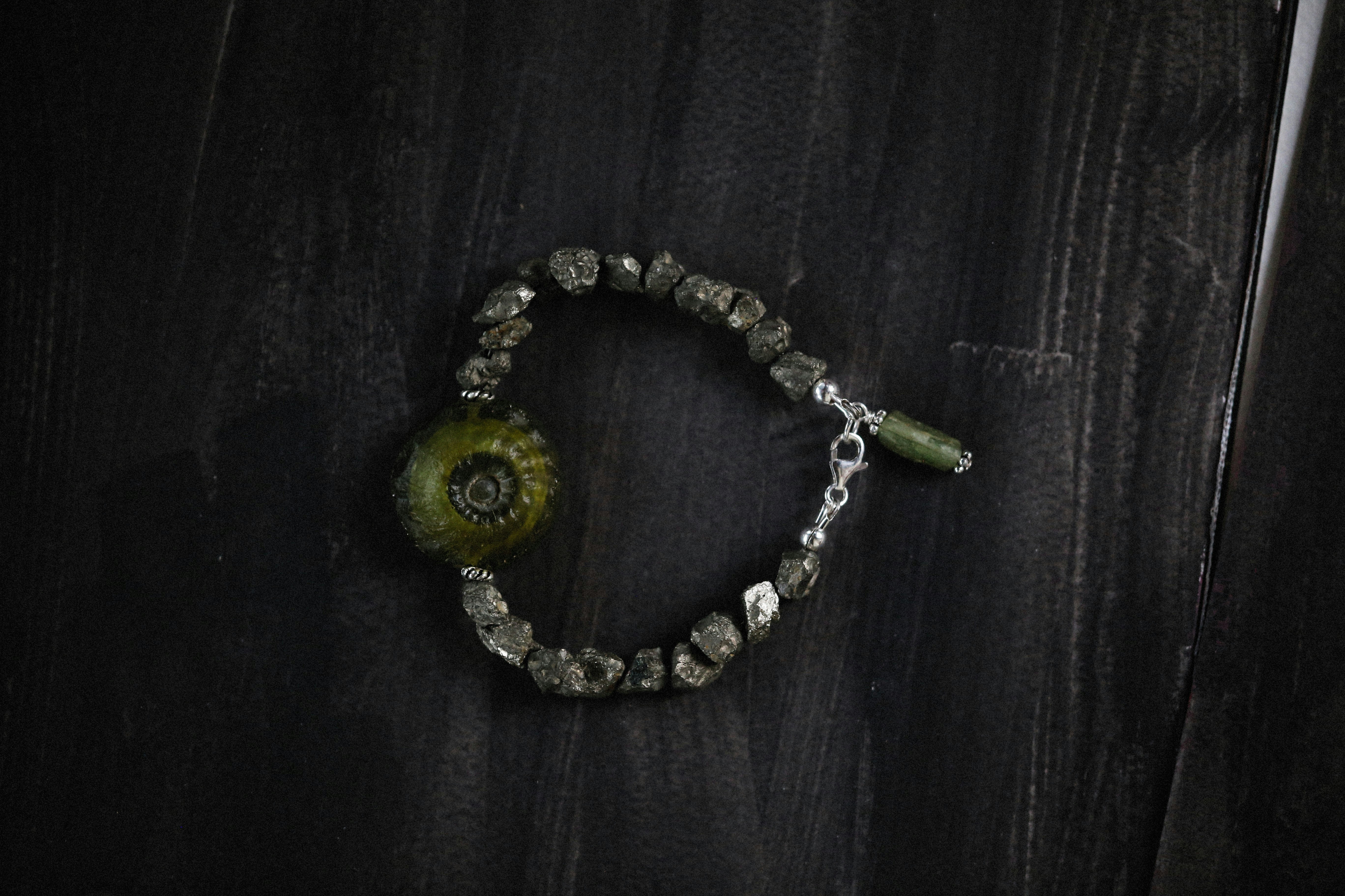 Verdant Centerpiece: A Rough Bead Bracelet on Charred Wood