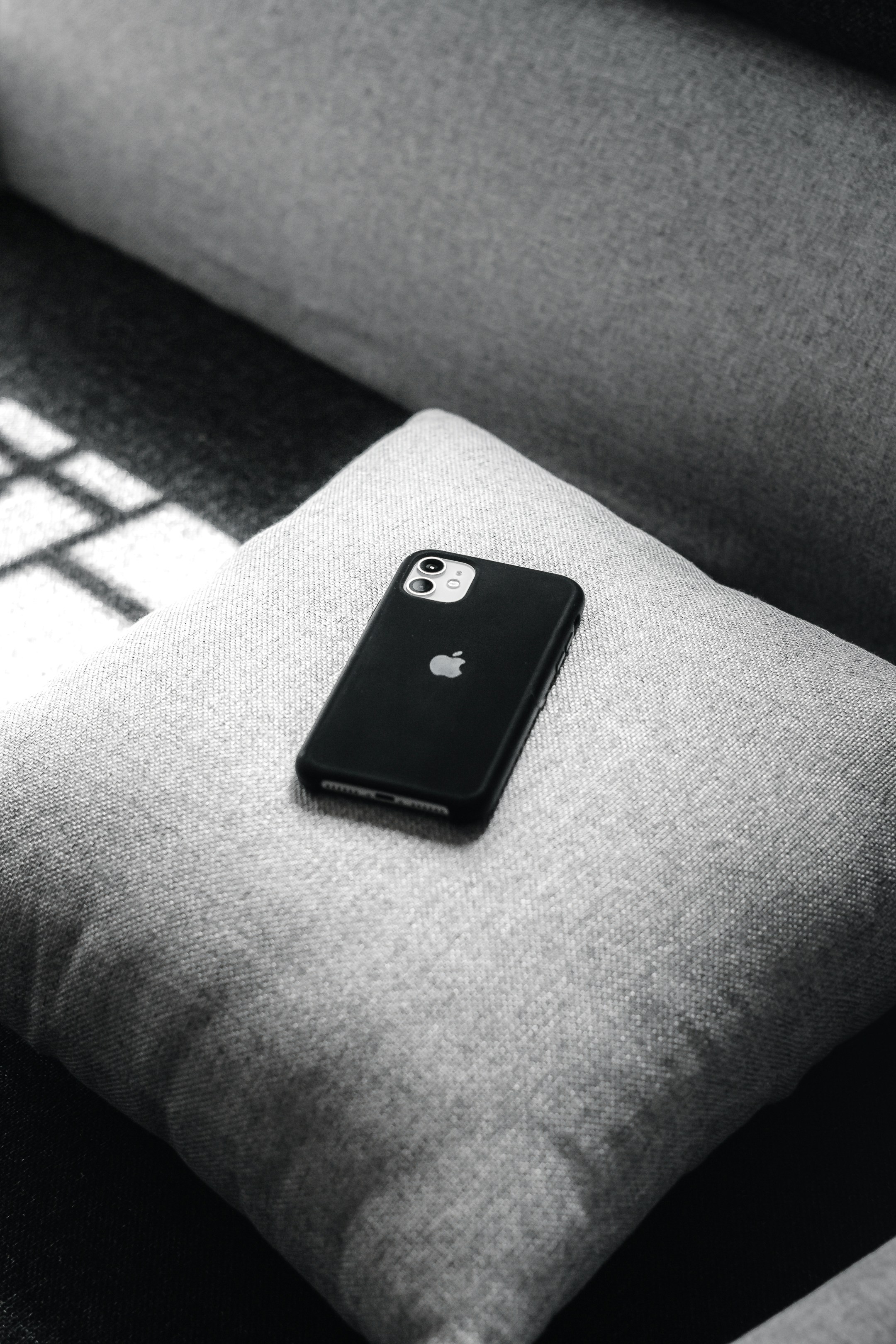 Monochrome Quiet: iPhone Repose on a Soft Grey Cushioned Surface