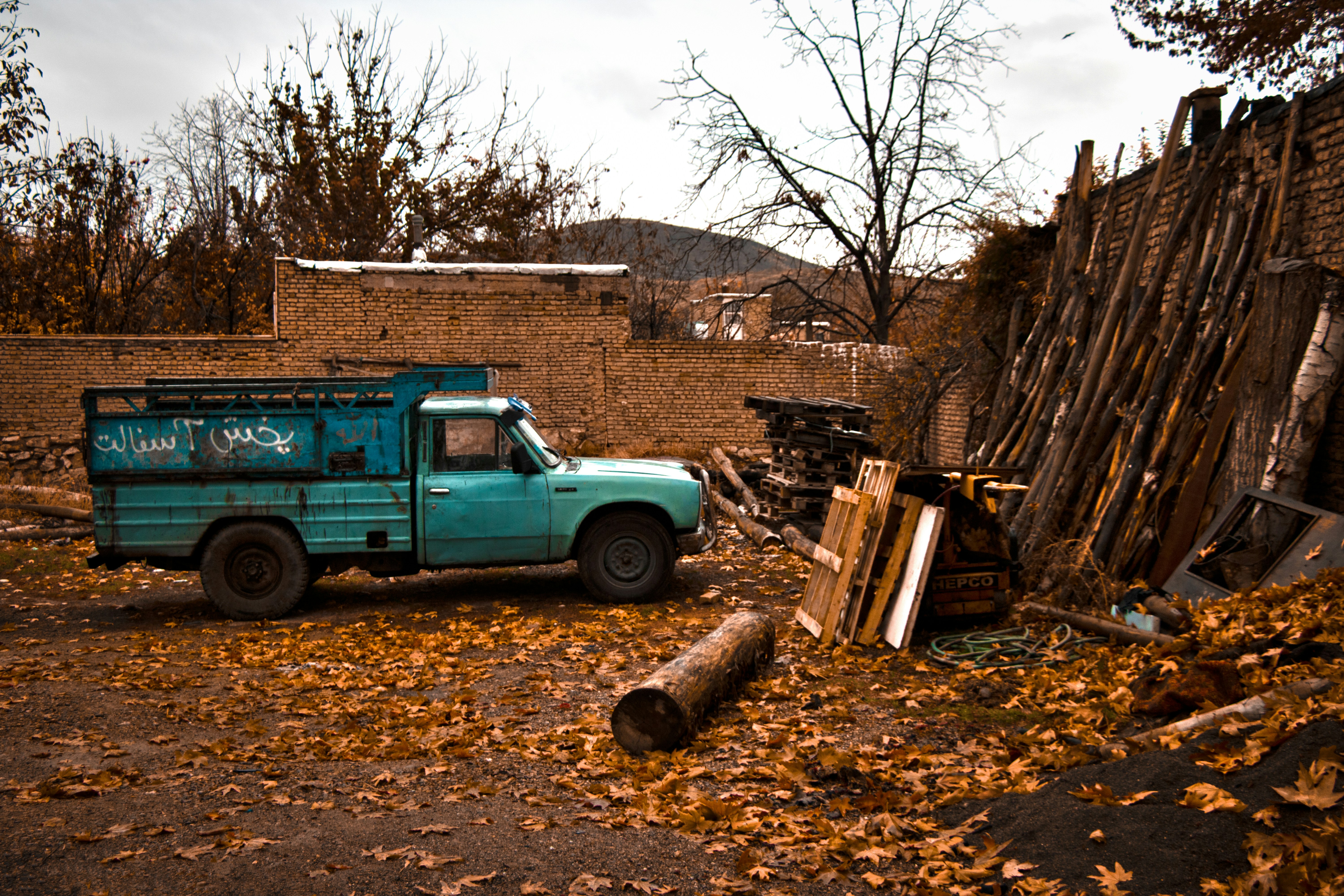 Turquoise Utility Truck Among Brick Debris and Autumn Leaves