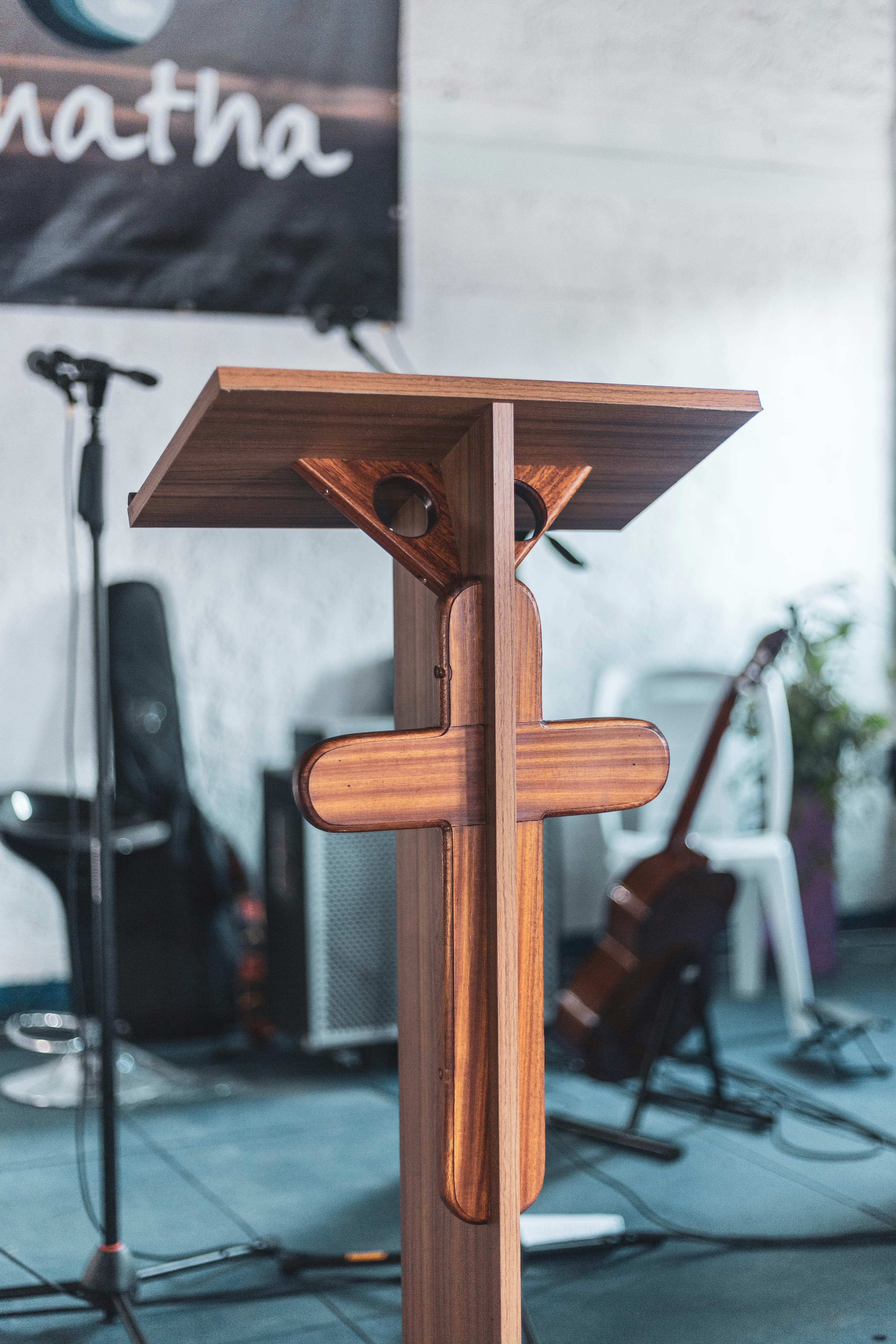 Elegant wooden pulpit with a cross design, set against a backdrop of musical instruments and a stage. The scene conveys a sense of community and faith.