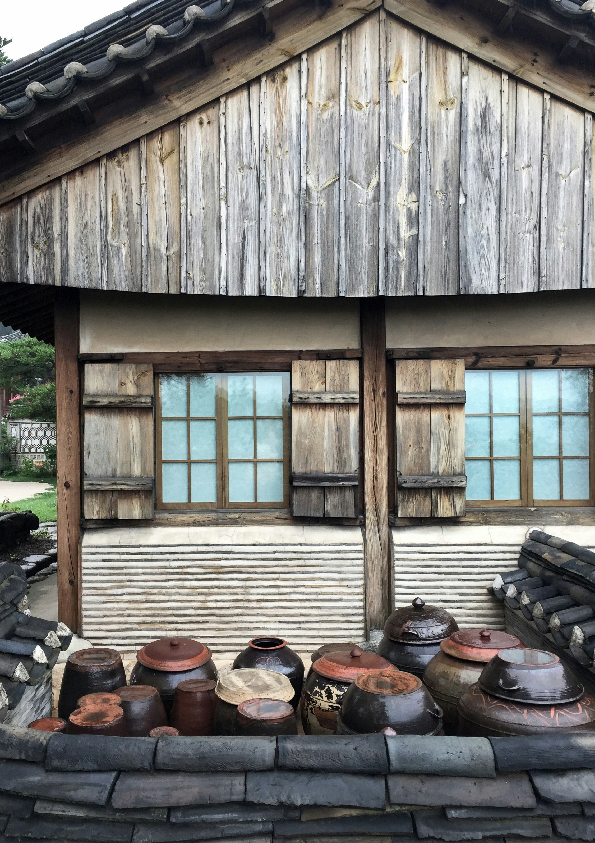 Symmetry in Weathered Timber: A Timber House Framed by Clay Jars