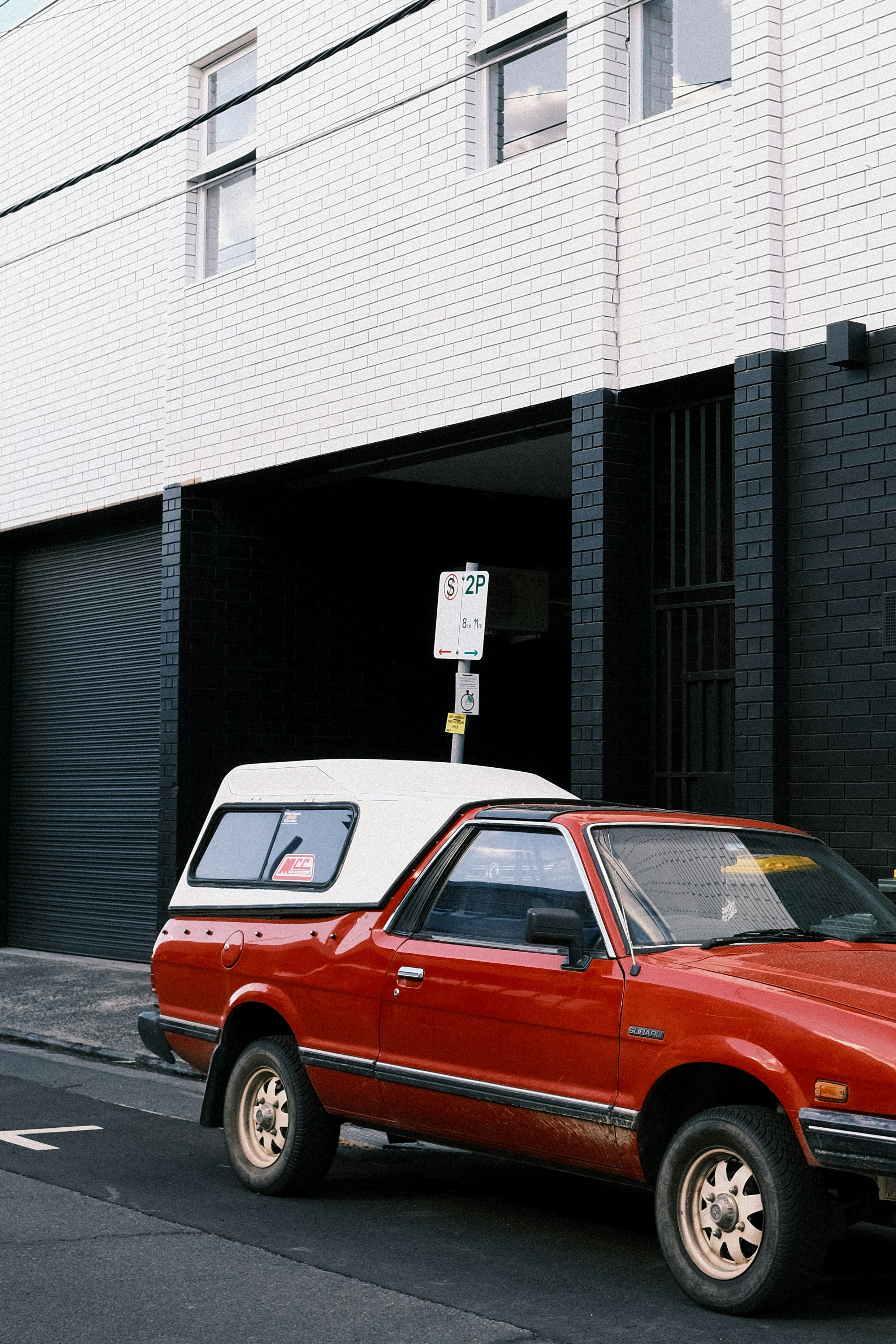 Ventured into the City: A Red Vintage Pickup Framed by Brick and Shadow