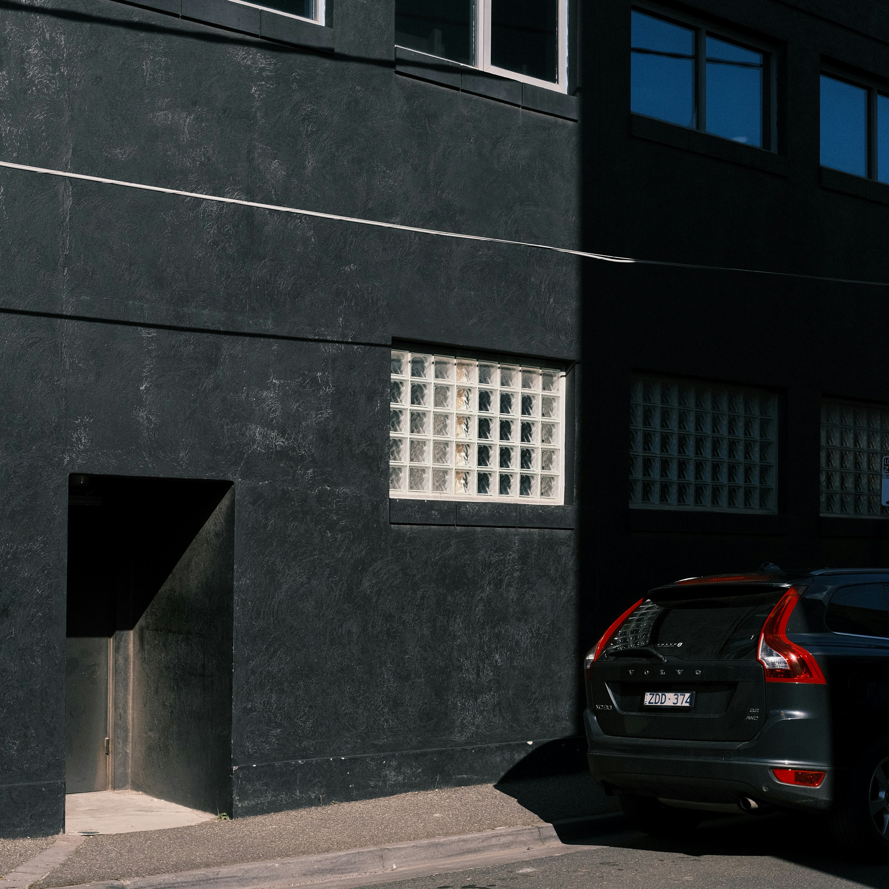 Doorway in a Velvet Facade: Sunlit Lines and a Parked SUV