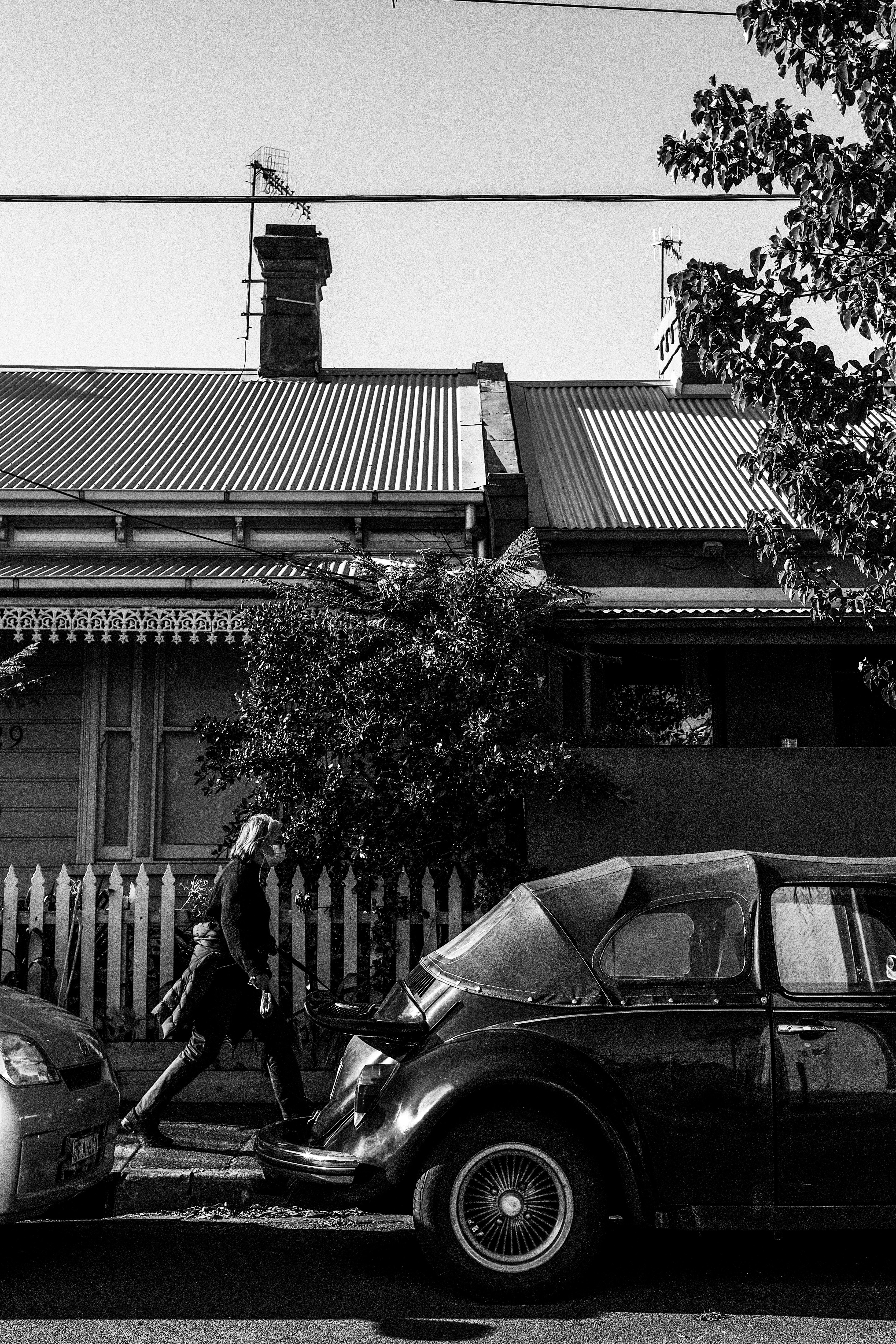 Monochrome Quiet on a Suburban Street: Pedestrian beside a Vintage Car