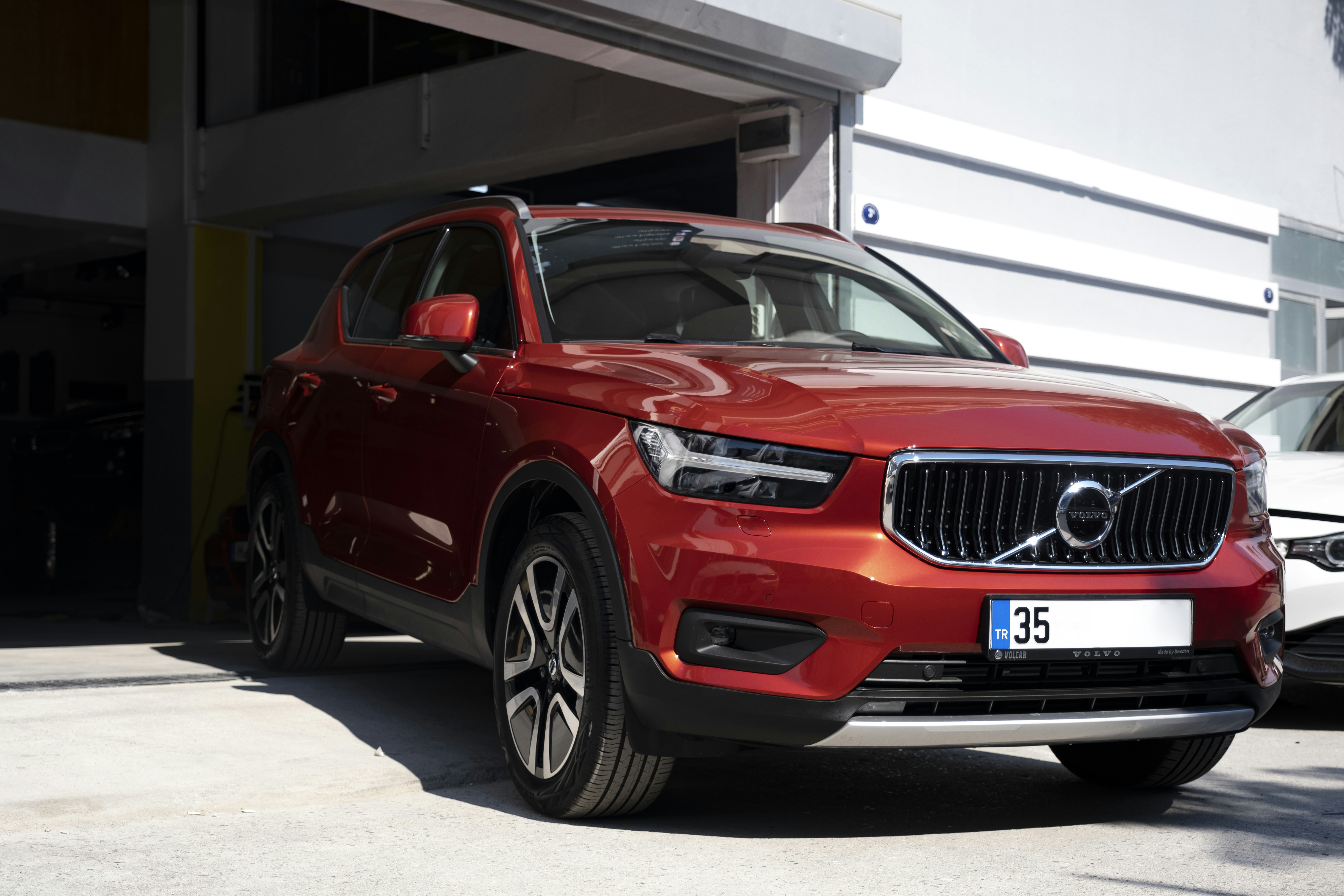 A red volvo car parked in front of a building photo – Free Car Image on ...