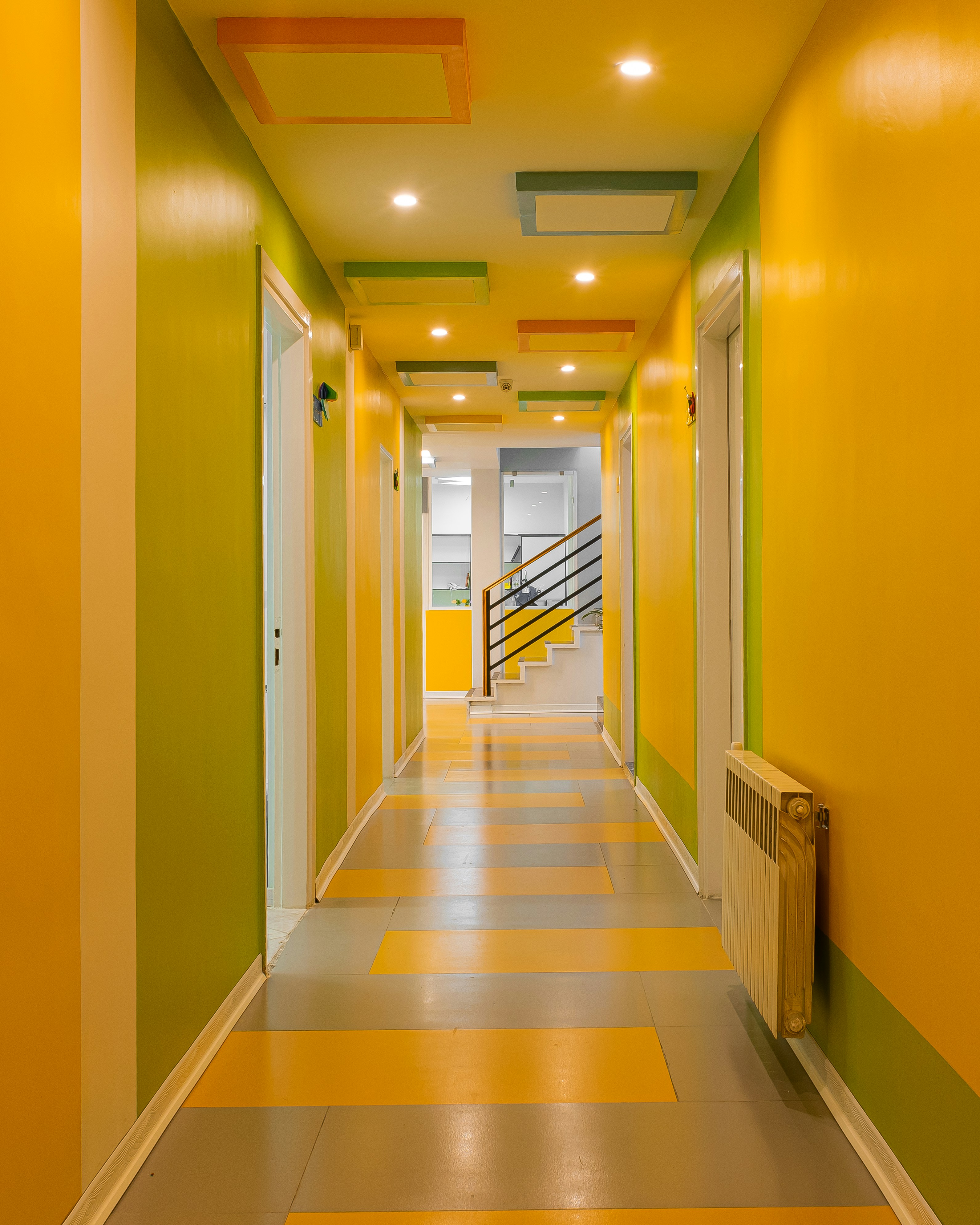 A long hallway with yellow and green walls photo – Free Corridor Image ...