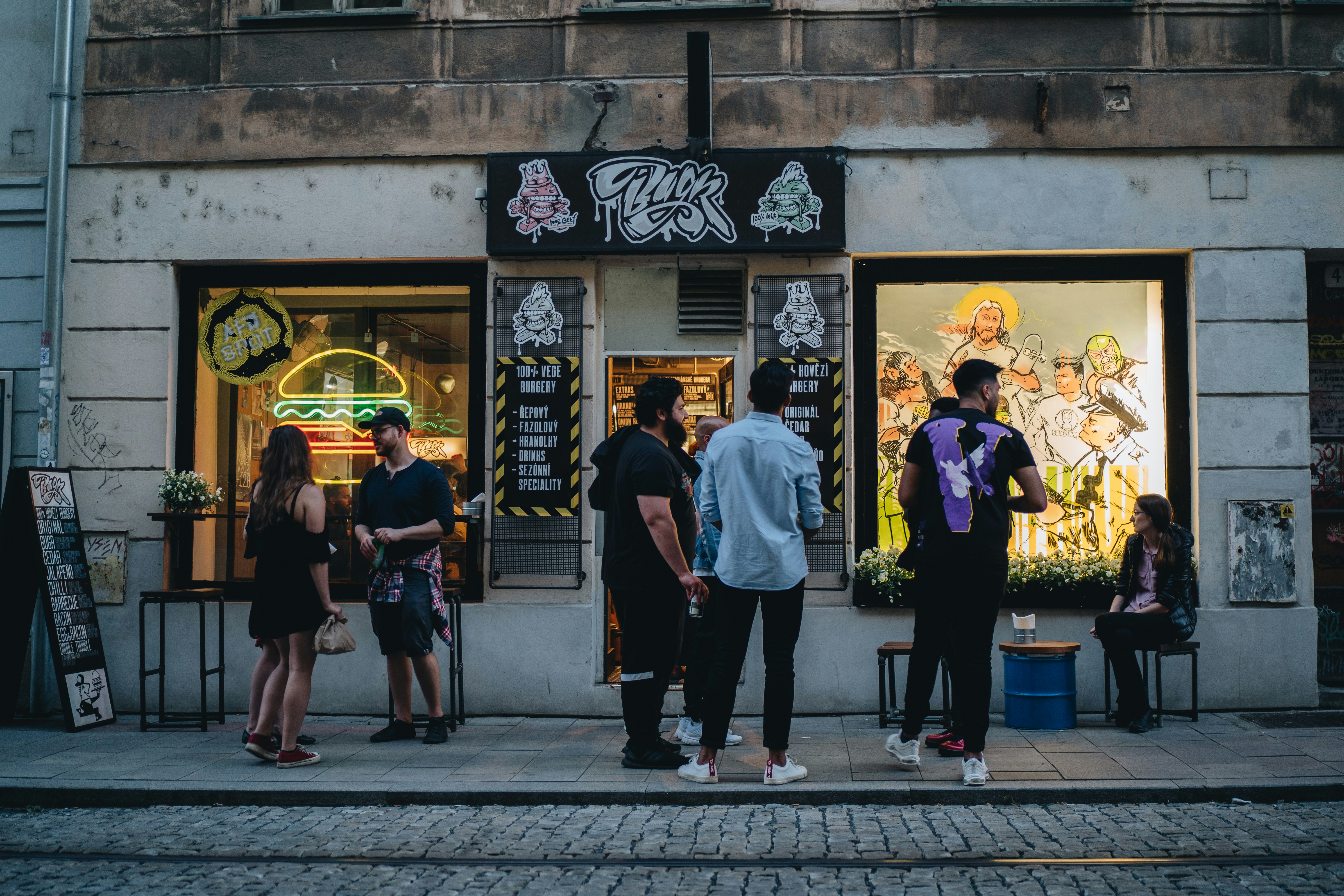 Neon Threshold: Evening Crowd Outside a Bohemian Café