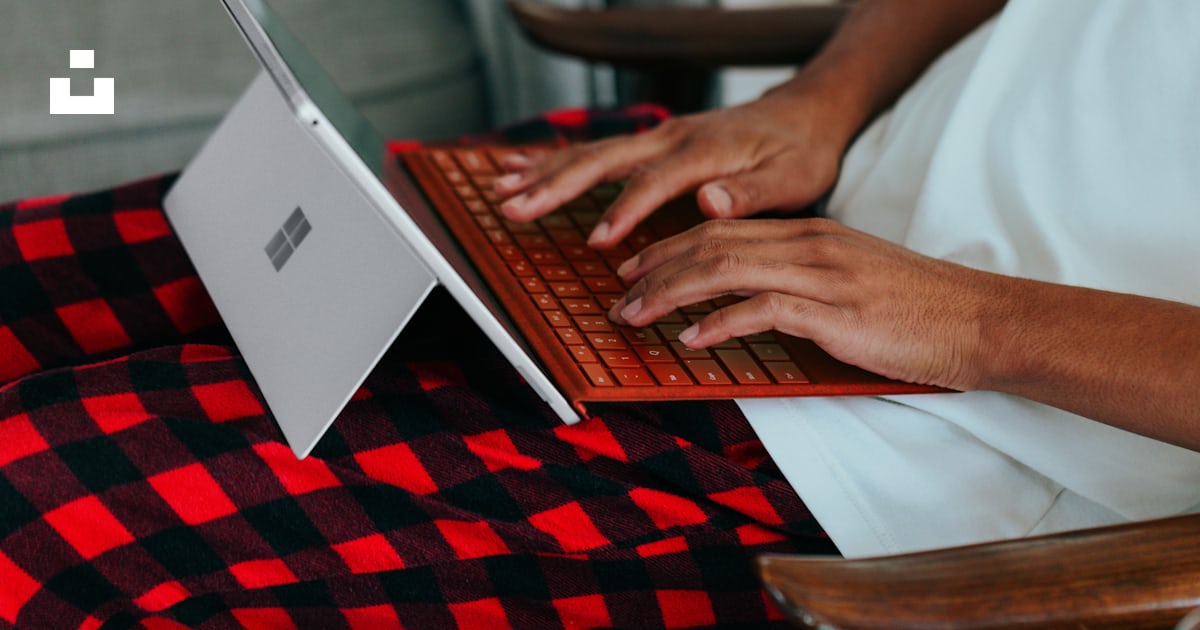 체크 무늬 잠옷을 입고 집에서 Surface 노트북을 사용하는 사람 사진 Unsplash의 무료 랩톱 이미지