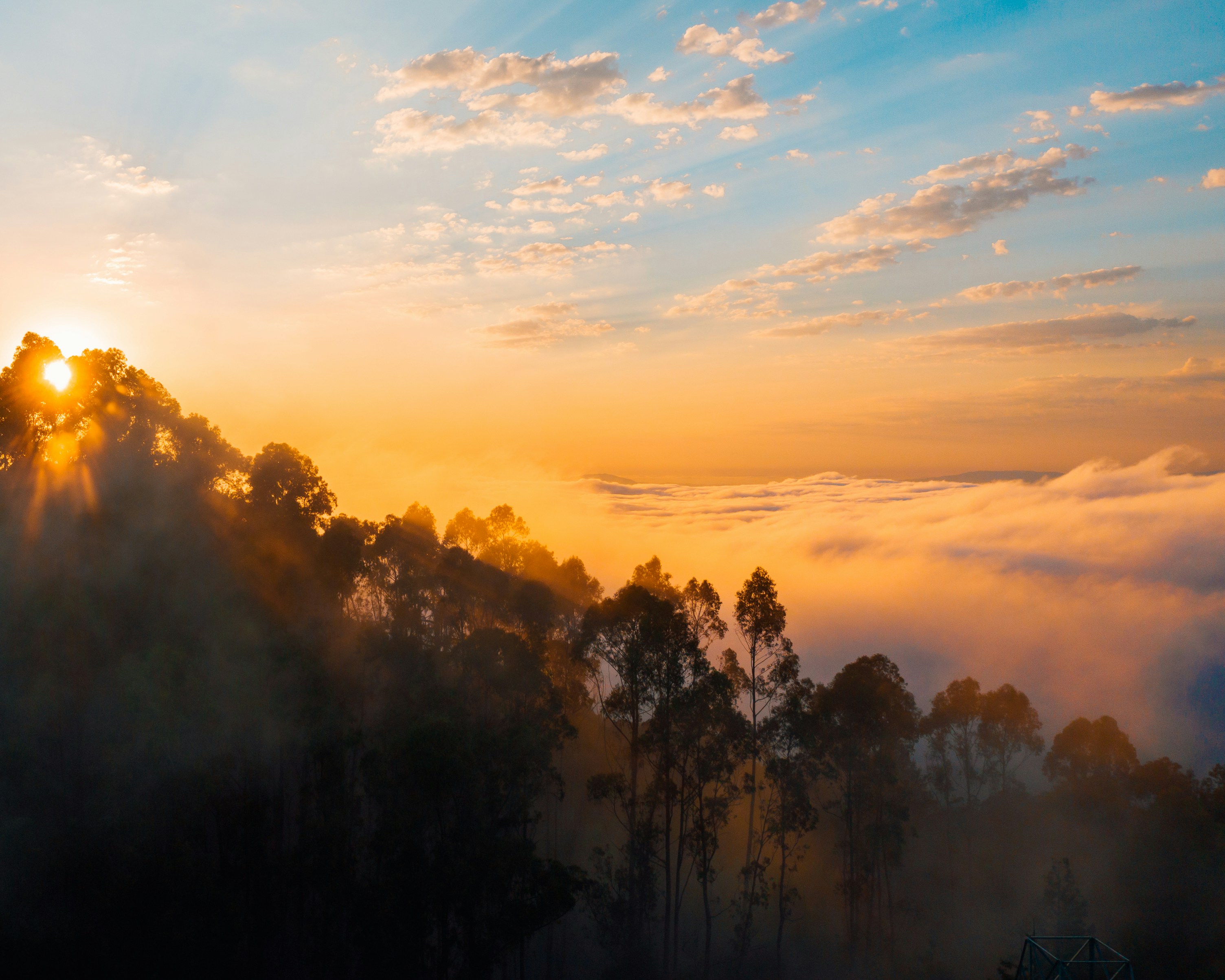 the sun is shining through the clouds above the trees