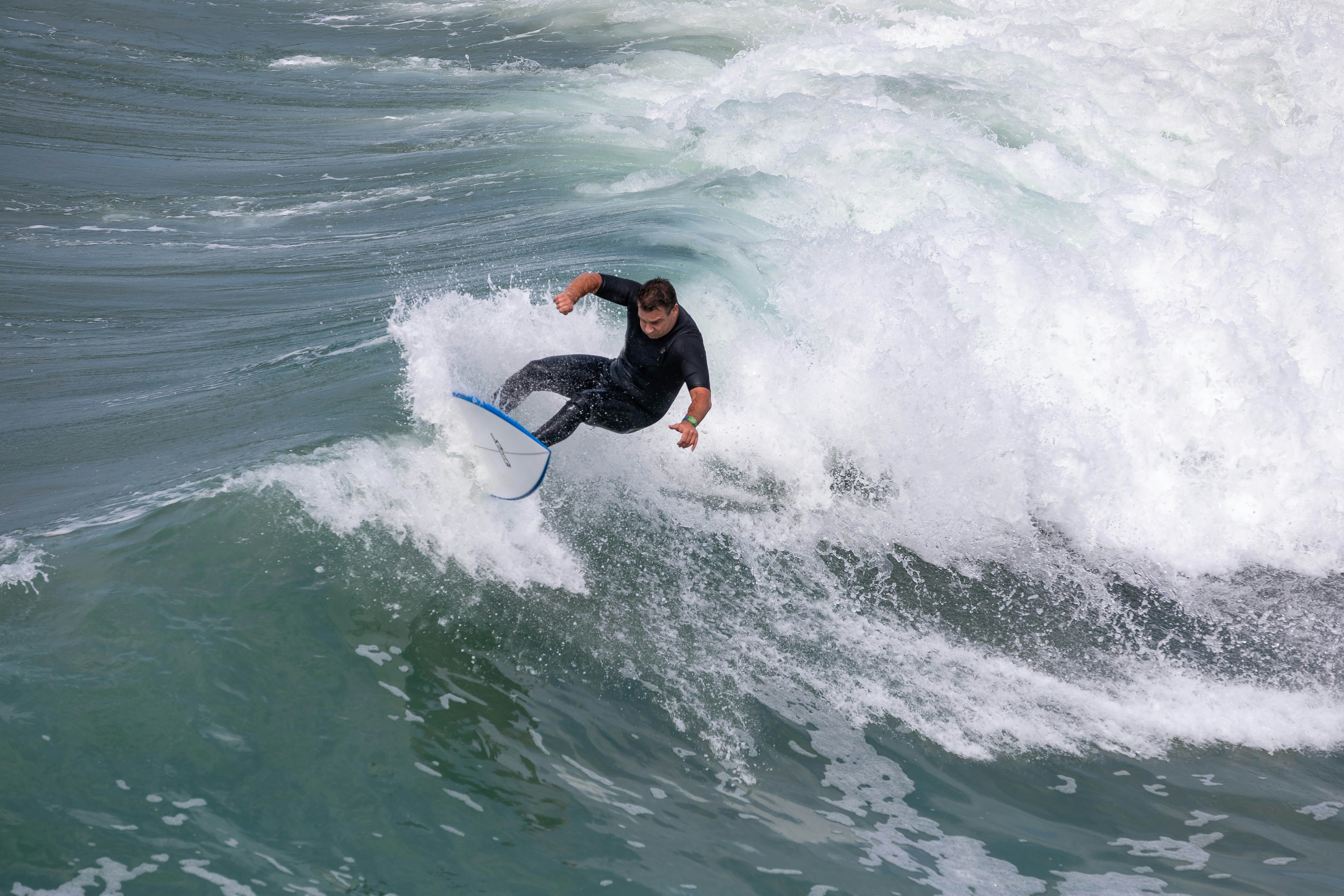 A man riding a wave on top of a surfboard photo – Free Human Image on ...