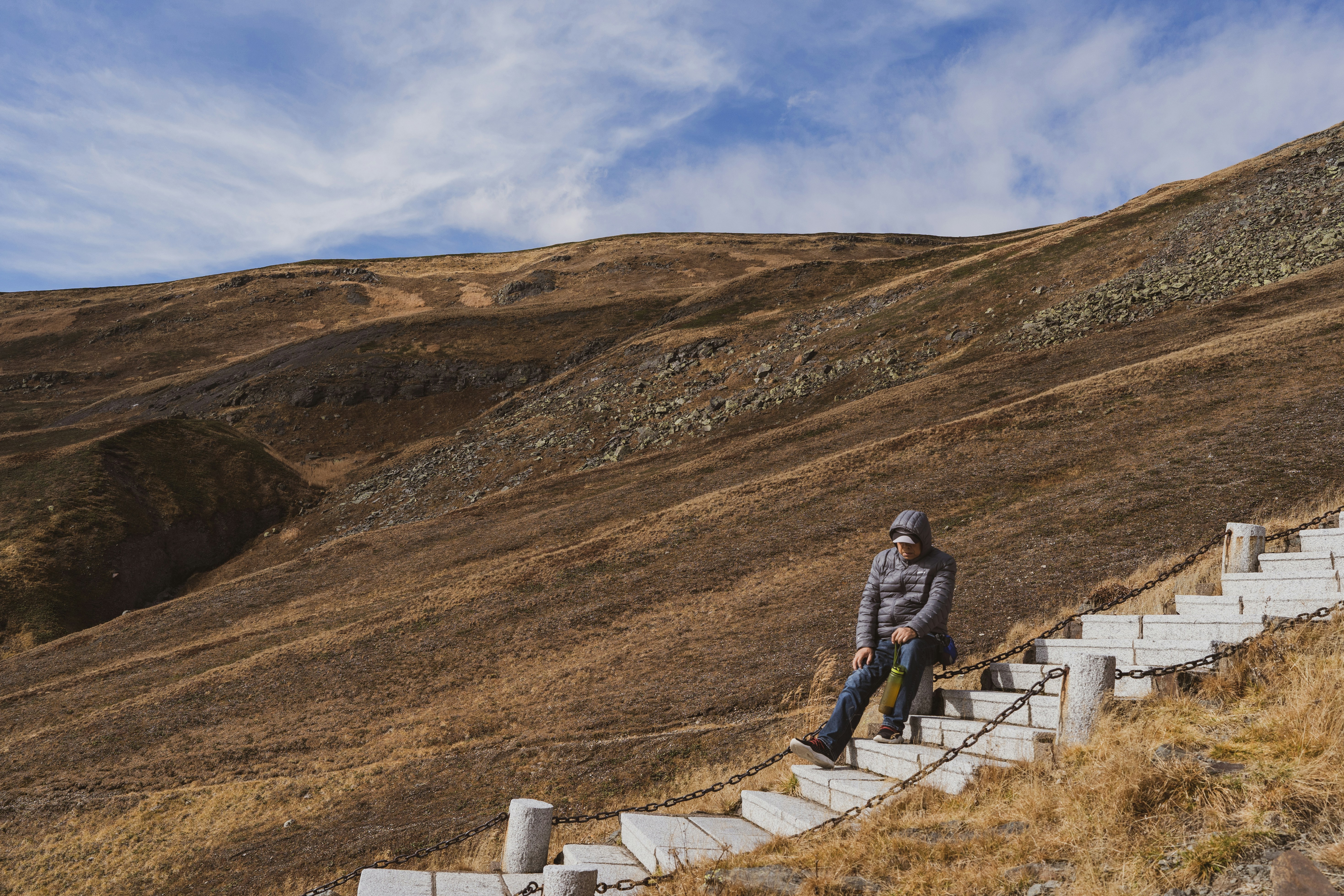 Terraced Ridge Quiet: A Lone Hiker on Windswept Steps Under a Wide Sky