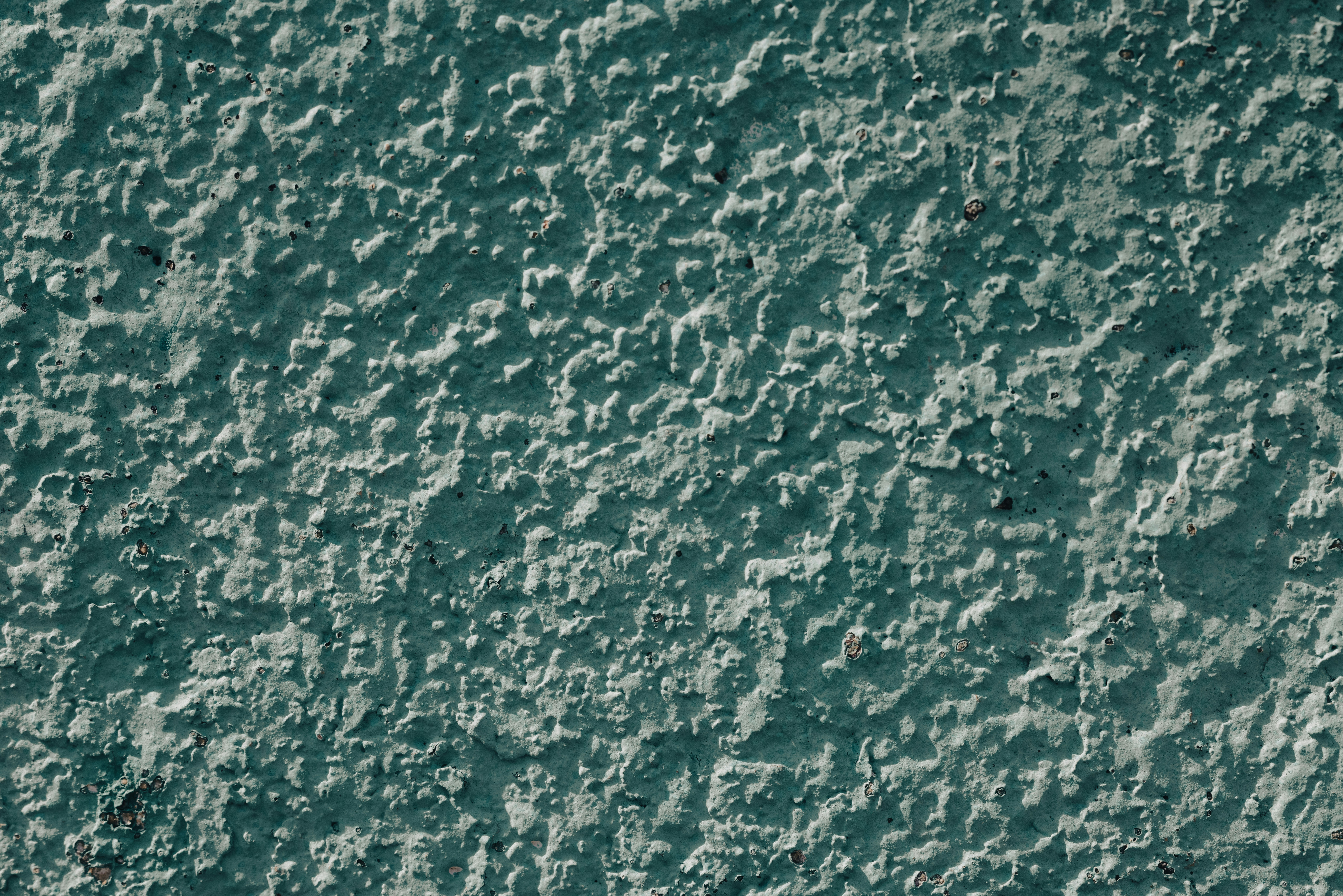 Close-up view of a textured wall featuring a unique turquoise finish, highlighting its intricate surface details.