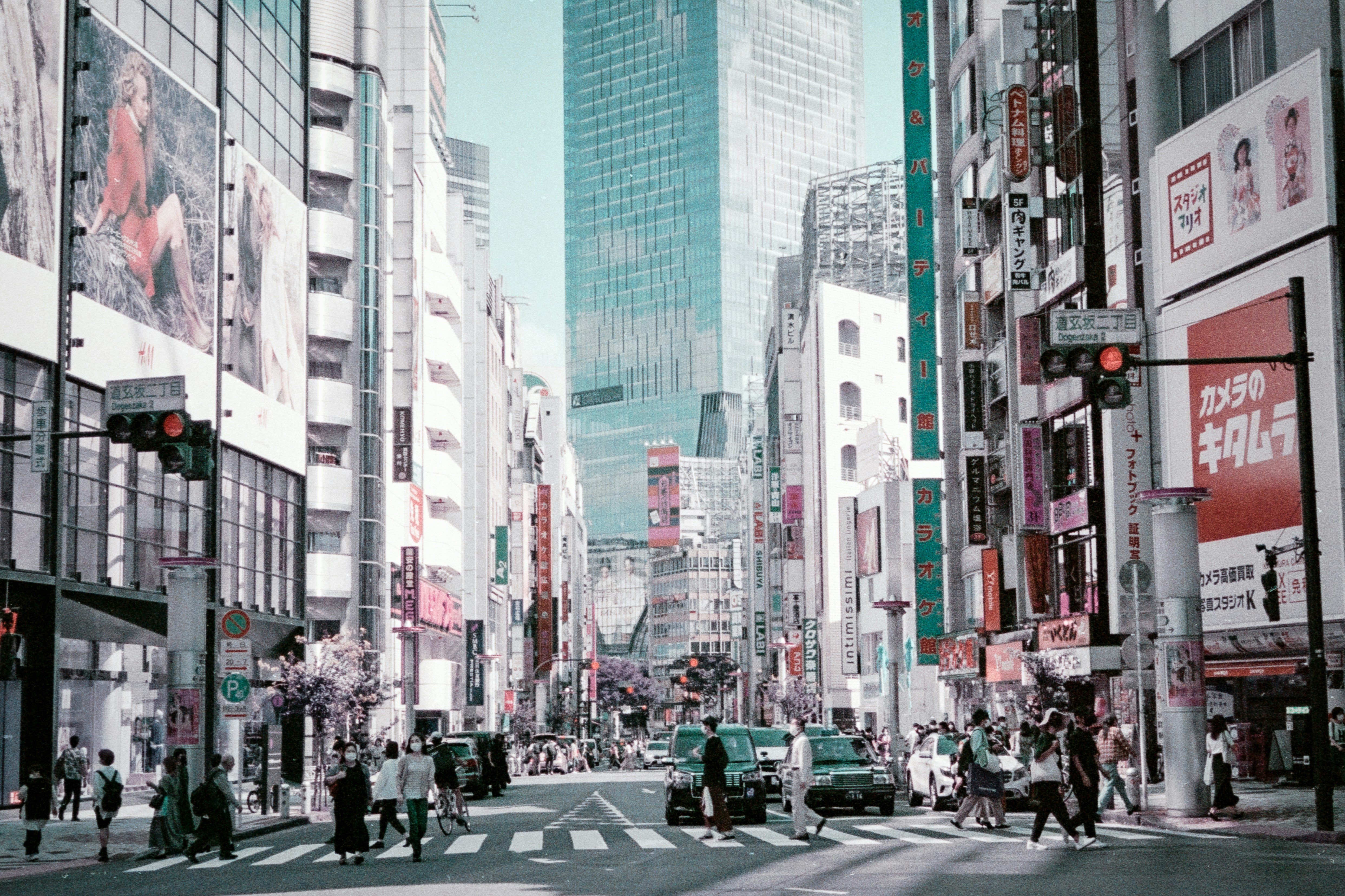 Bustling city intersection filled with pedestrians and vehicles, surrounded by vibrant advertisements and towering skyscrapers.