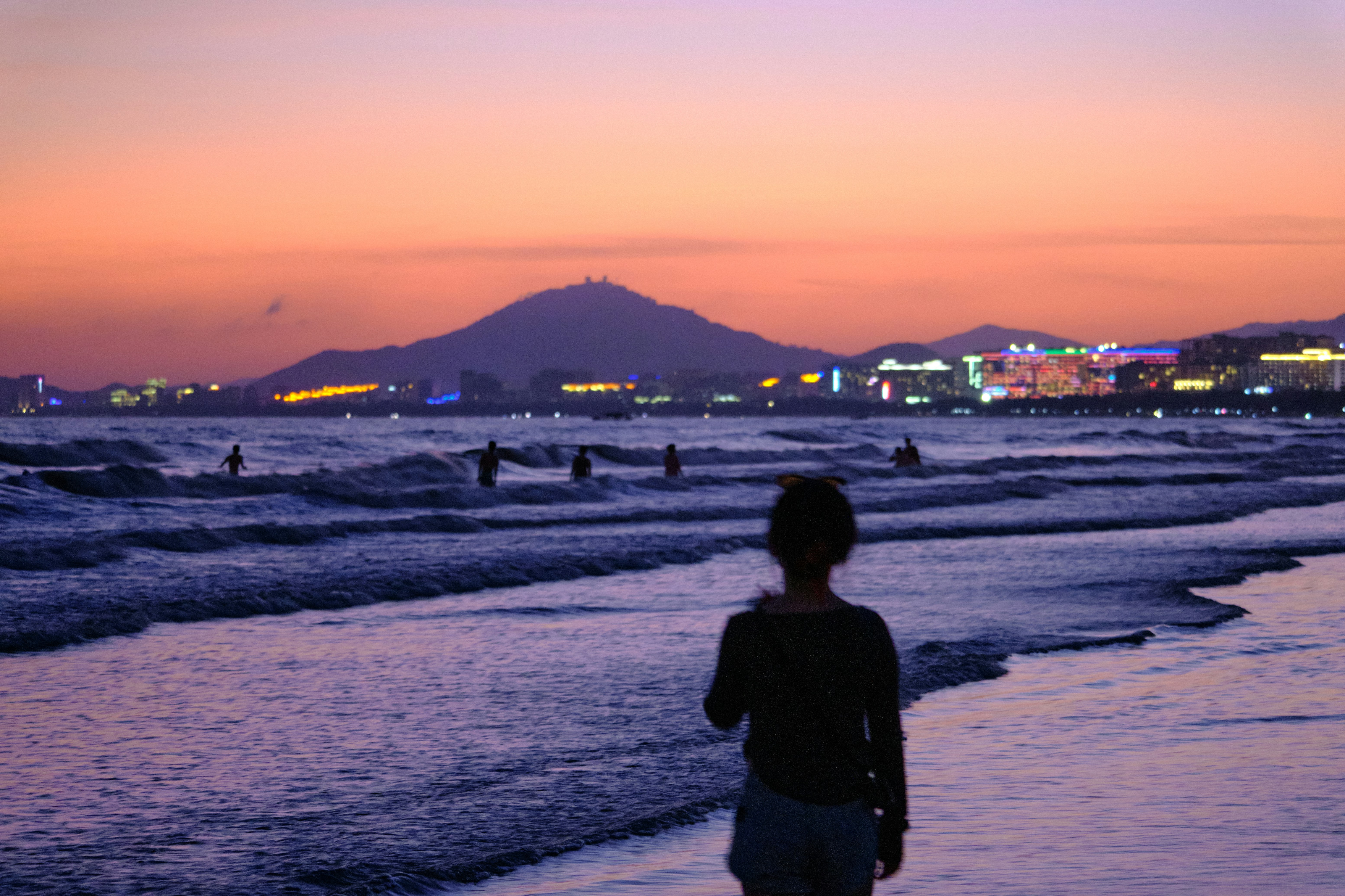 a woman standing on top of a beach next to the ocean