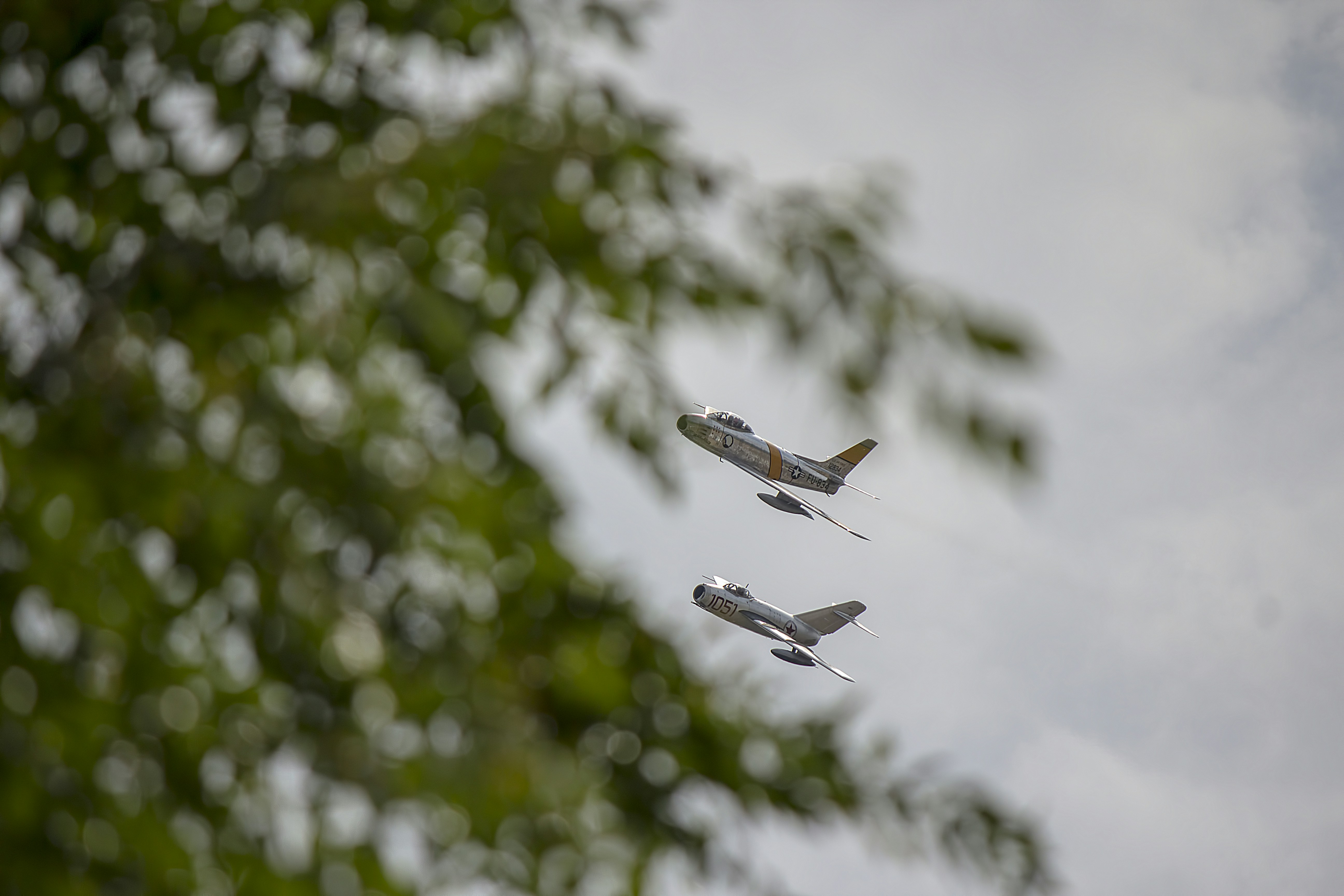 Two airplanes flying in the sky with trees in the background photo ...