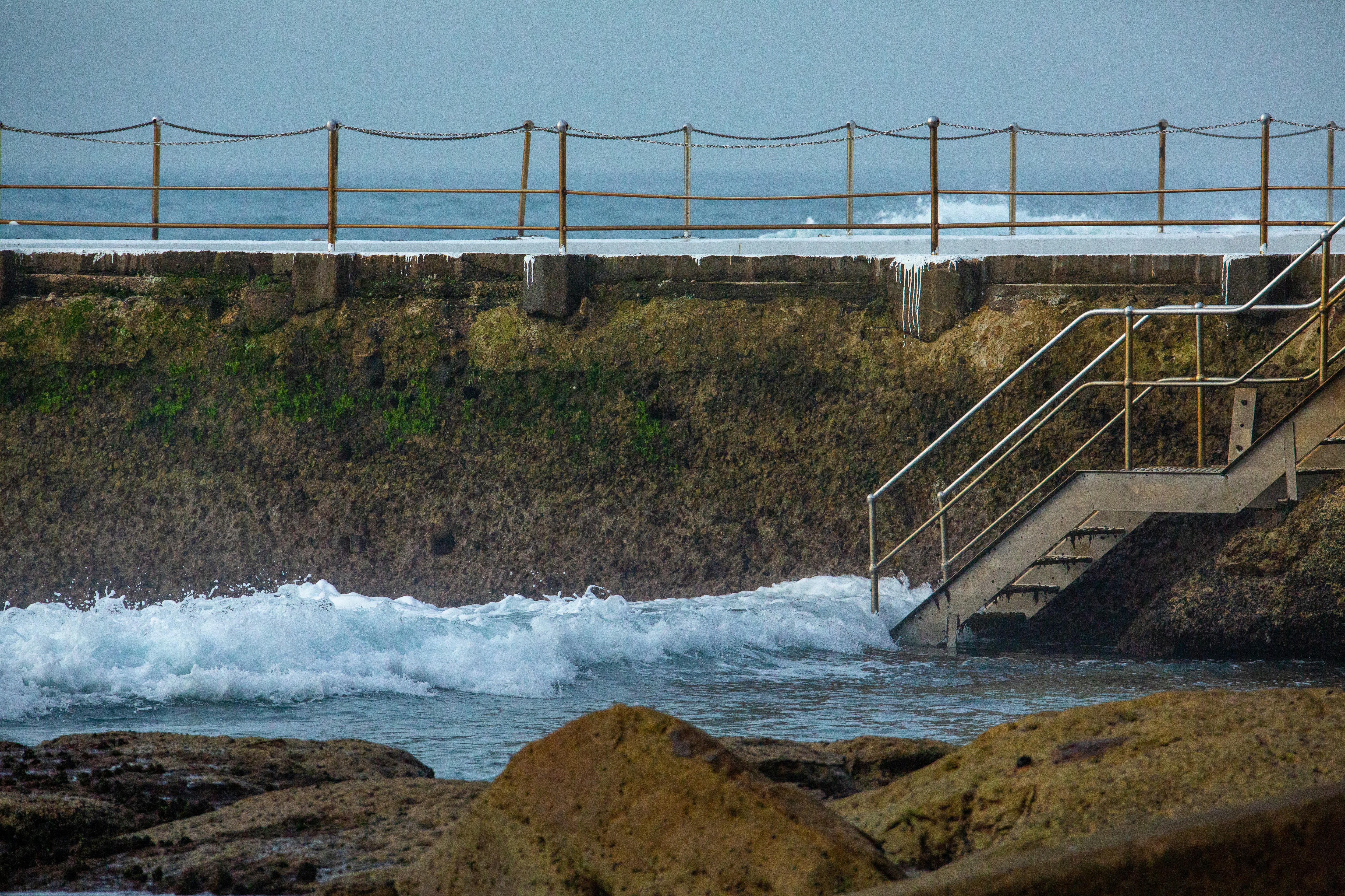 Railing and Tide: A Staircase Framed by a Weathered Sea Wall