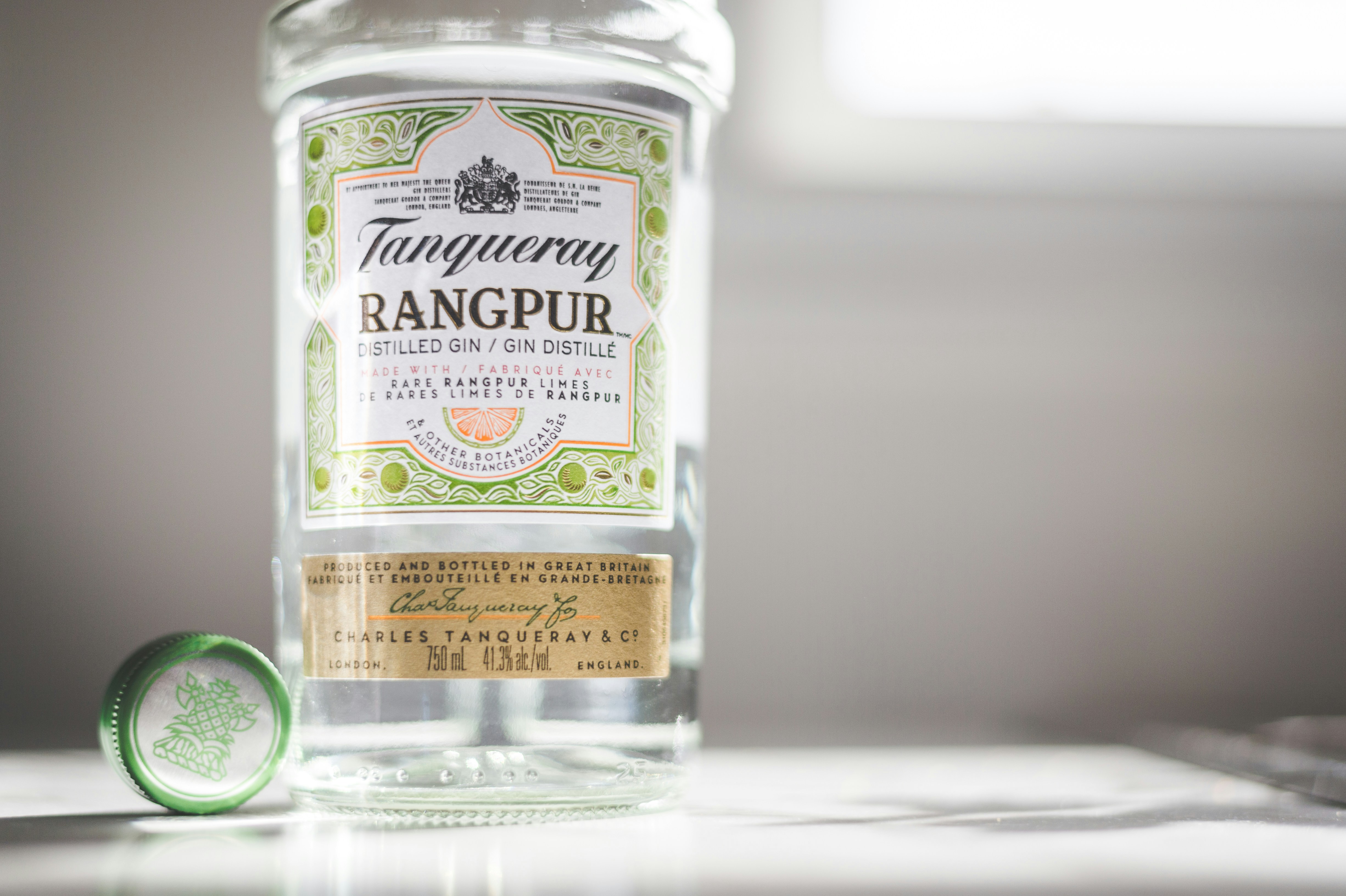 Tanqueray Rangpur bottle and cap on a surface with soft natural light.